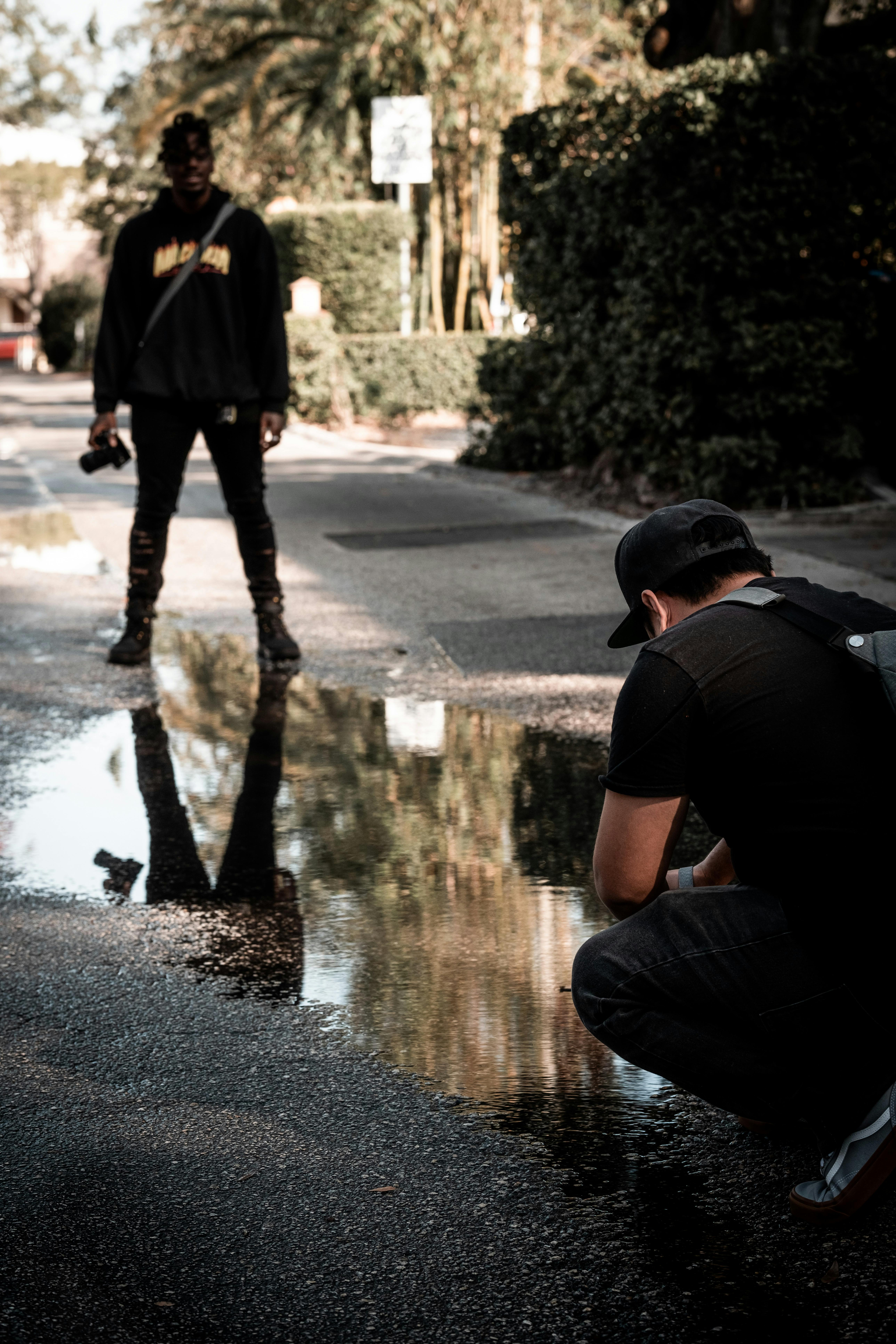 A man kneeling down in the middle of a puddle · Free Stock Photo