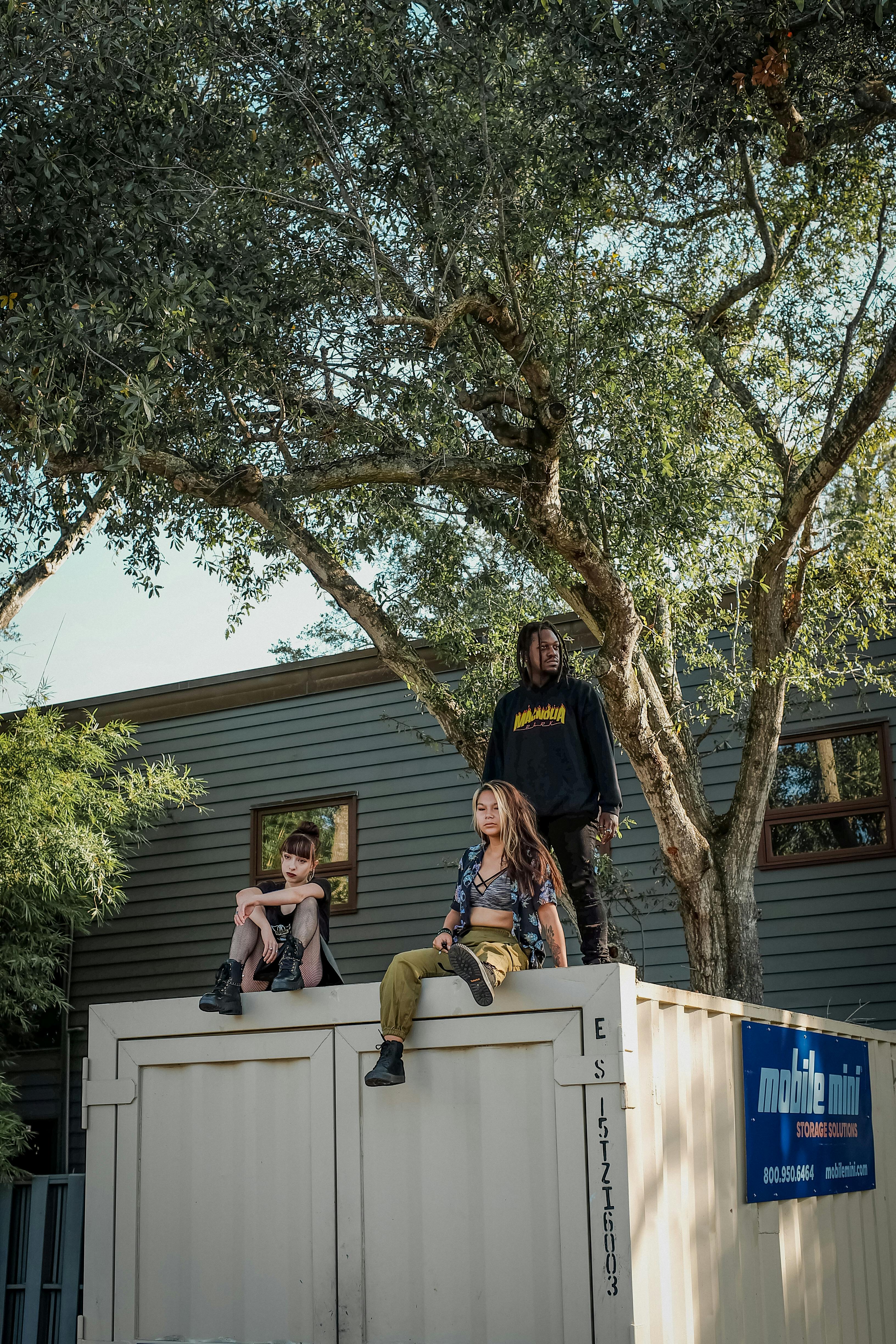 Three people sitting on top of a shipping container · Free Stock Photo