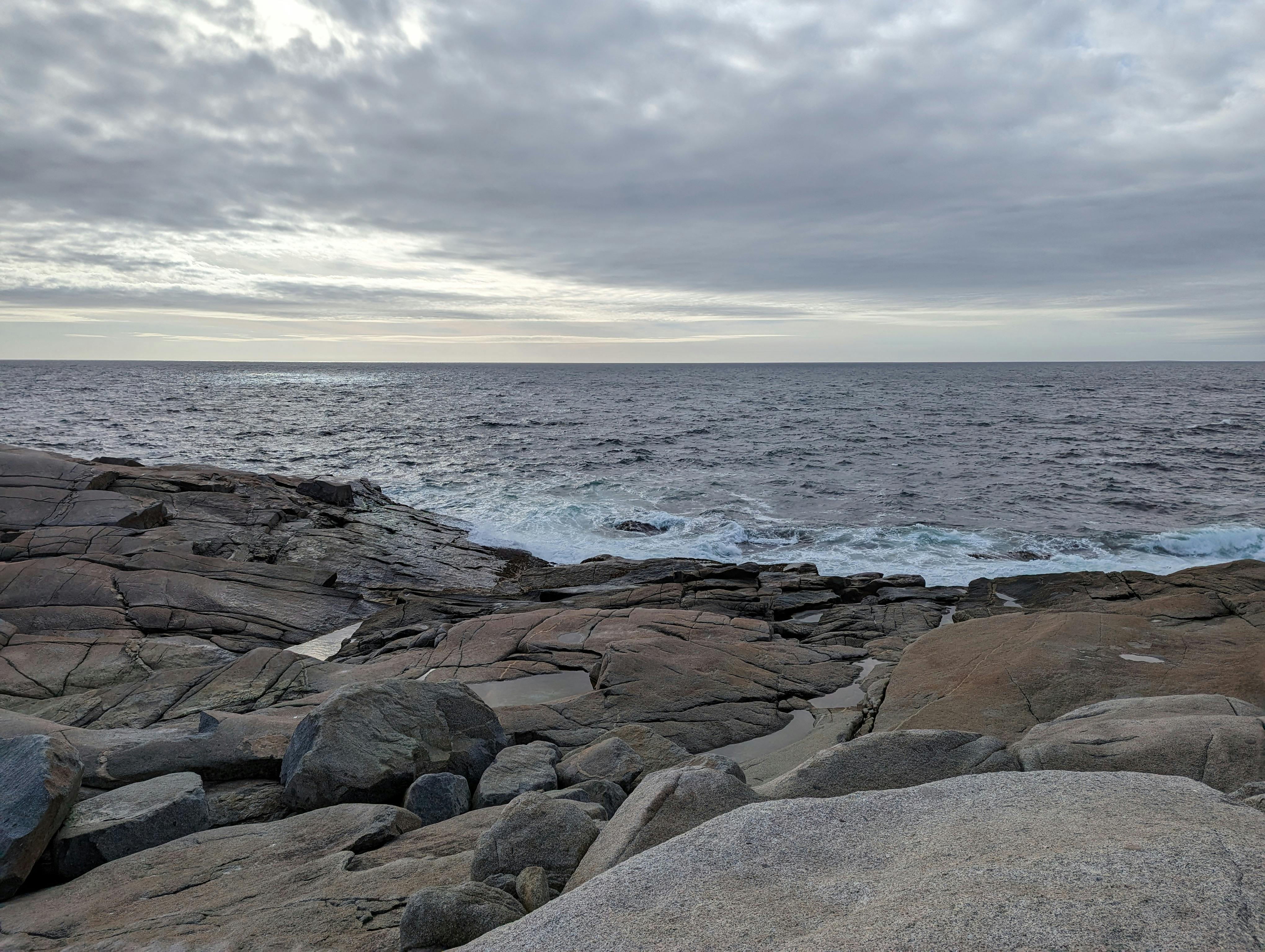Waves Breaking on a Rocky Shore Under a Cloudy Sky · Free Stock Photo