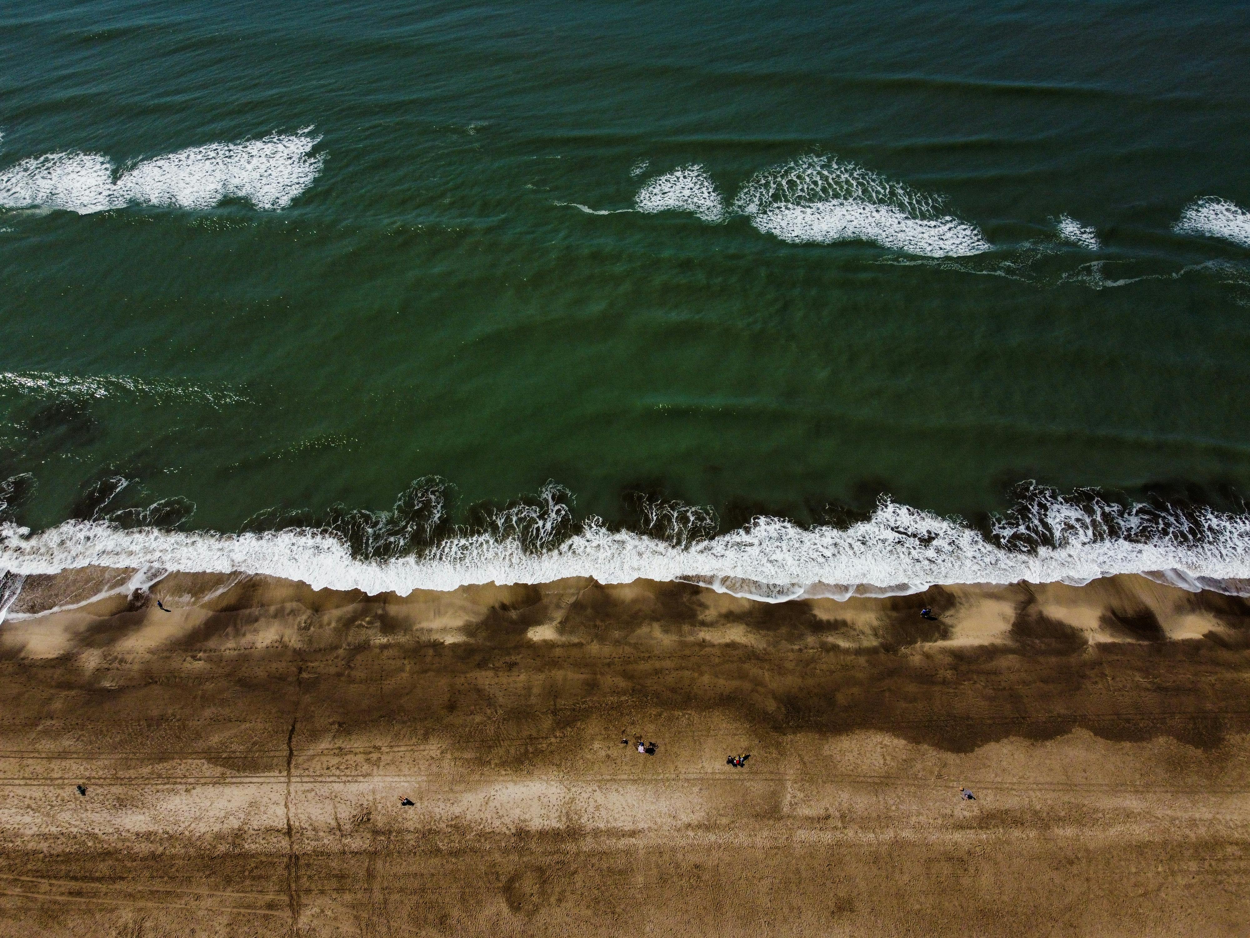 Drone Shot of Two People Walking at the Beach · Free Stock Photo