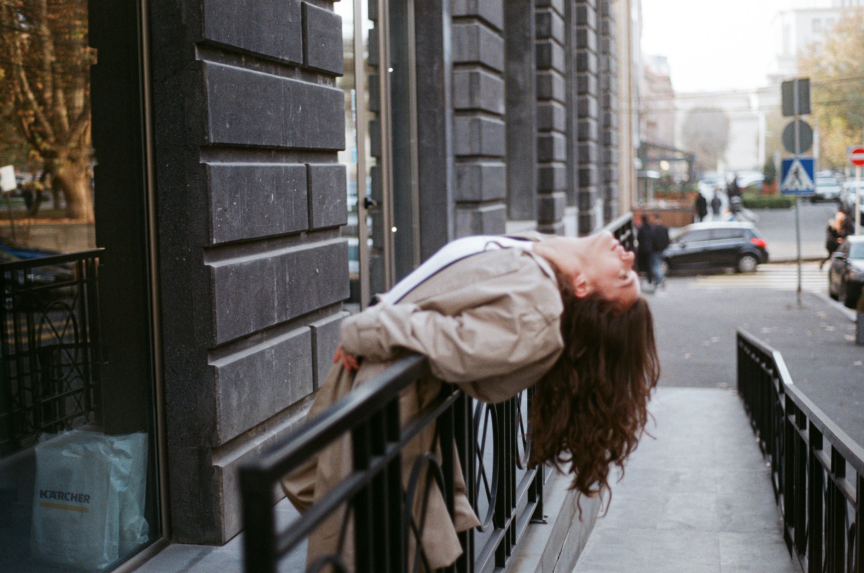 Young Woman Hanging Over a Railing on the Sidewalk · Free Stock Photo
