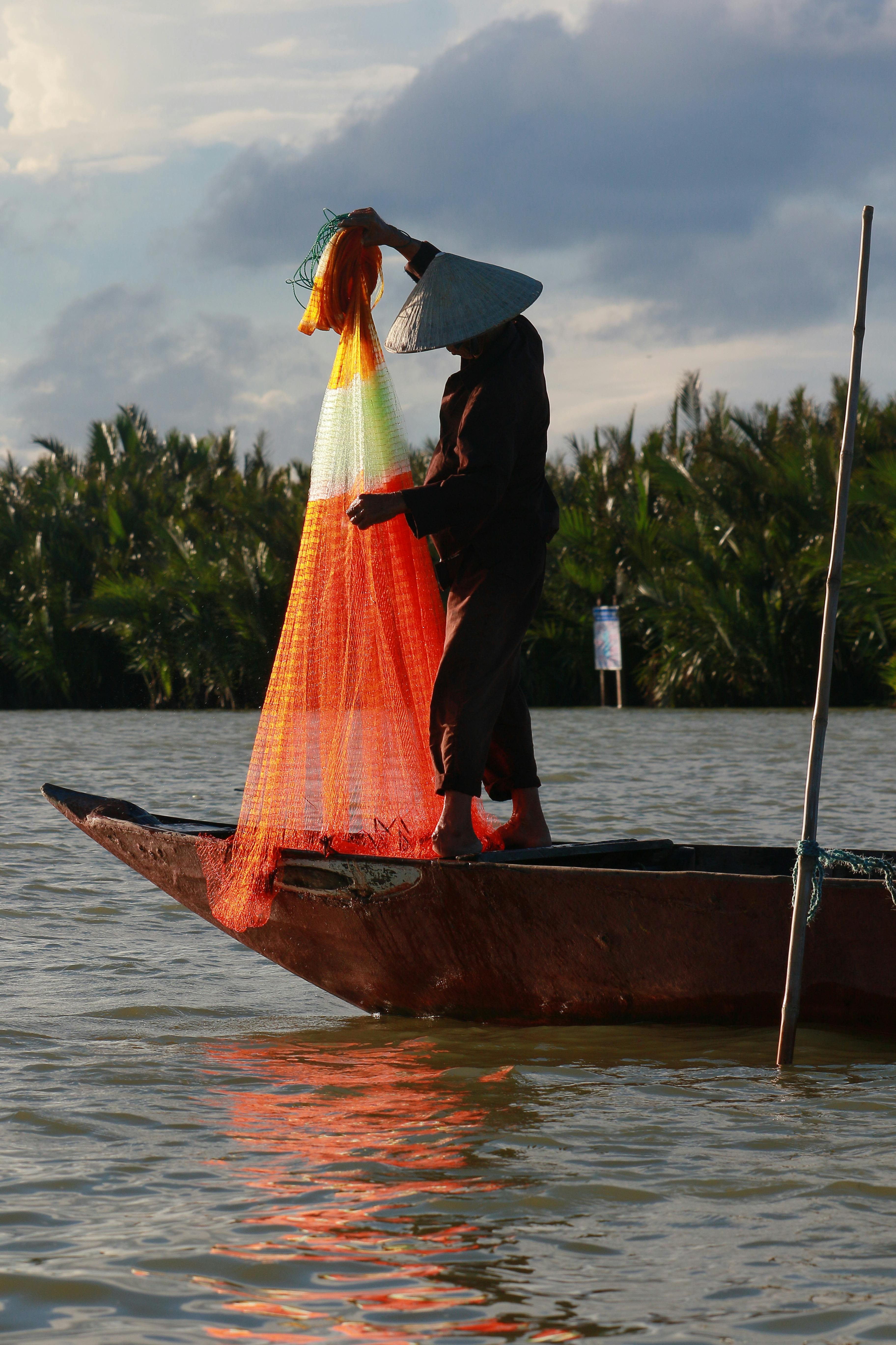 Fisherman in Rowboat with Fishing Net · Free Stock Photo