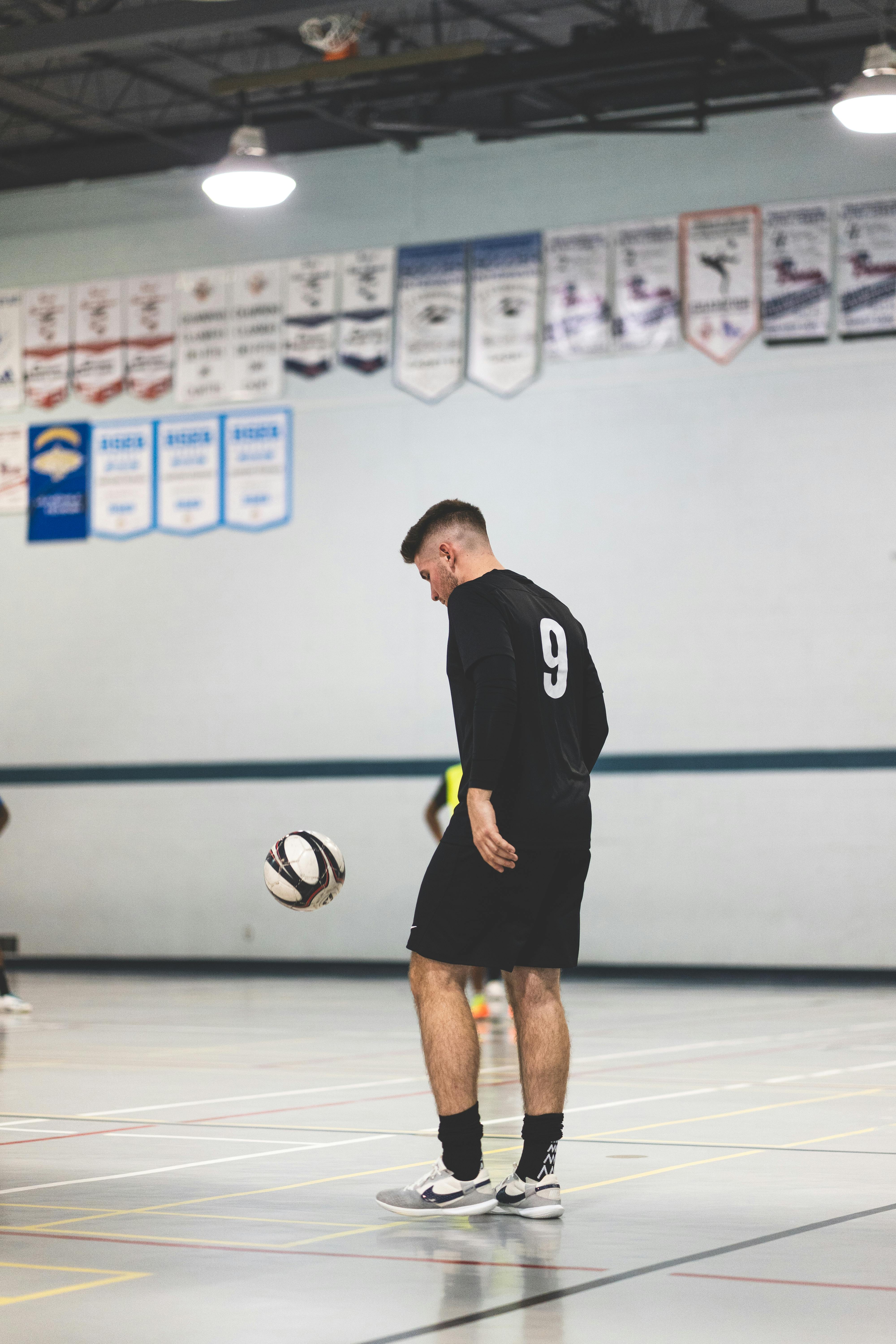 Man Playing Football on a Sports Hall · Free Stock Photo