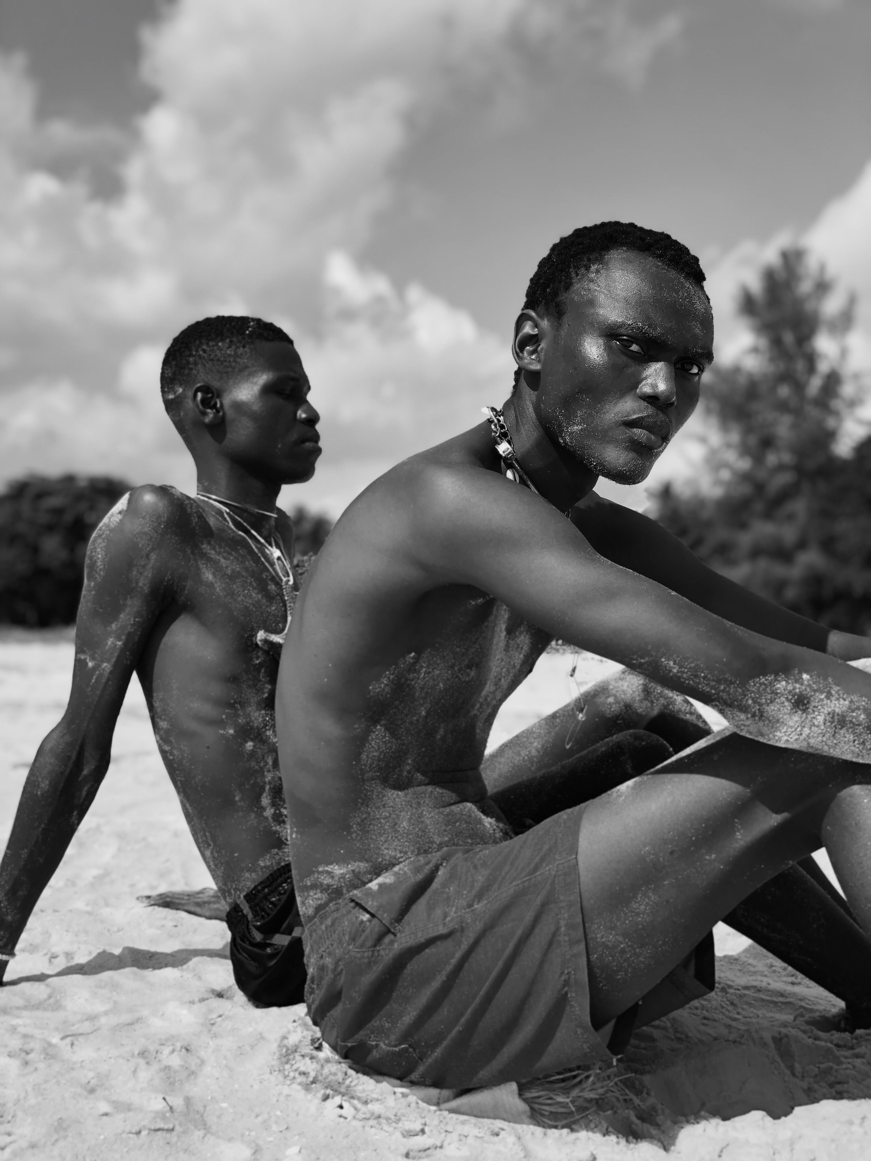 Grayscale Photography of Men Sitting on a Sandy Shore · Free Stock Photo