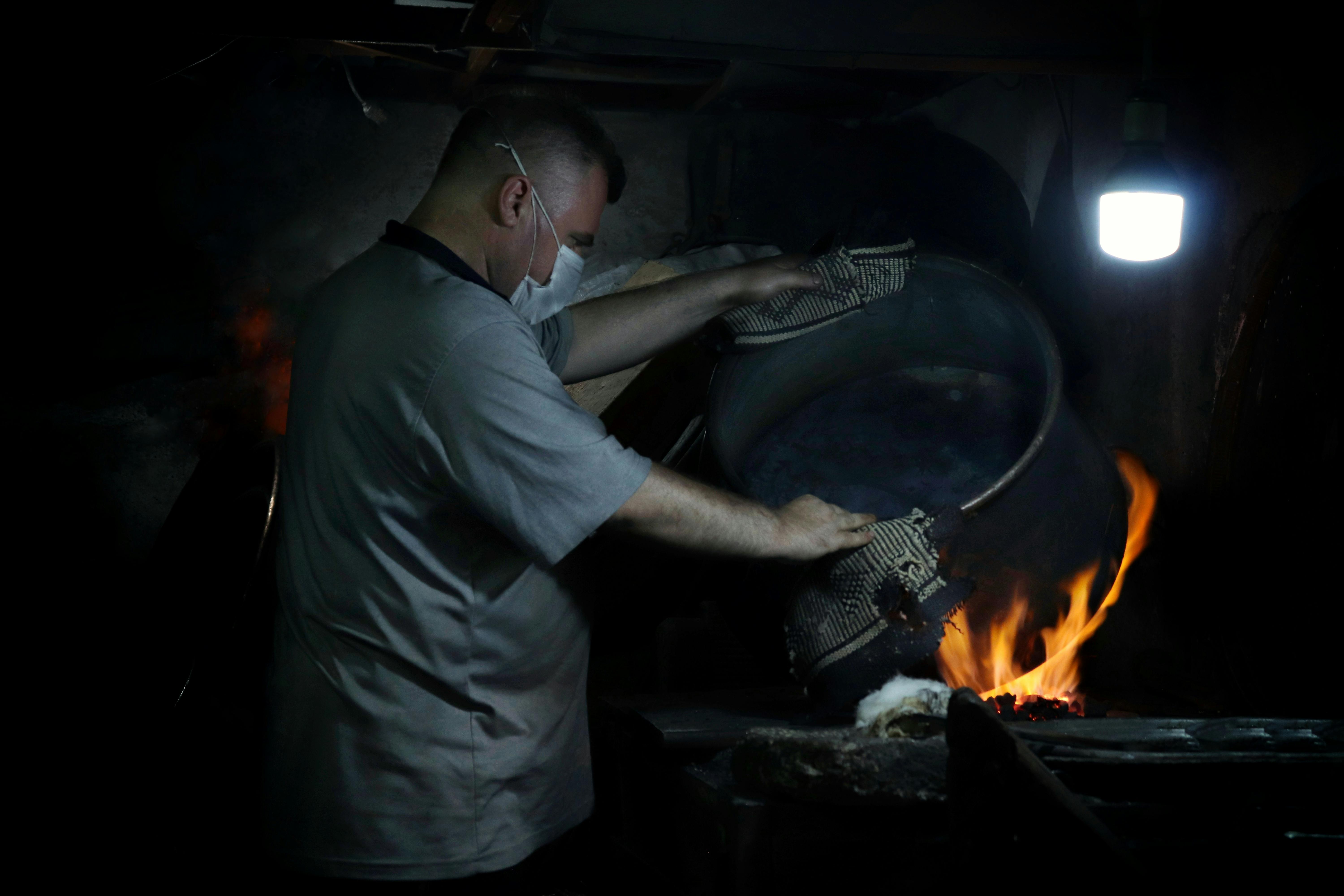 Man Holding Pot over Fire at Workshop · Free Stock Photo