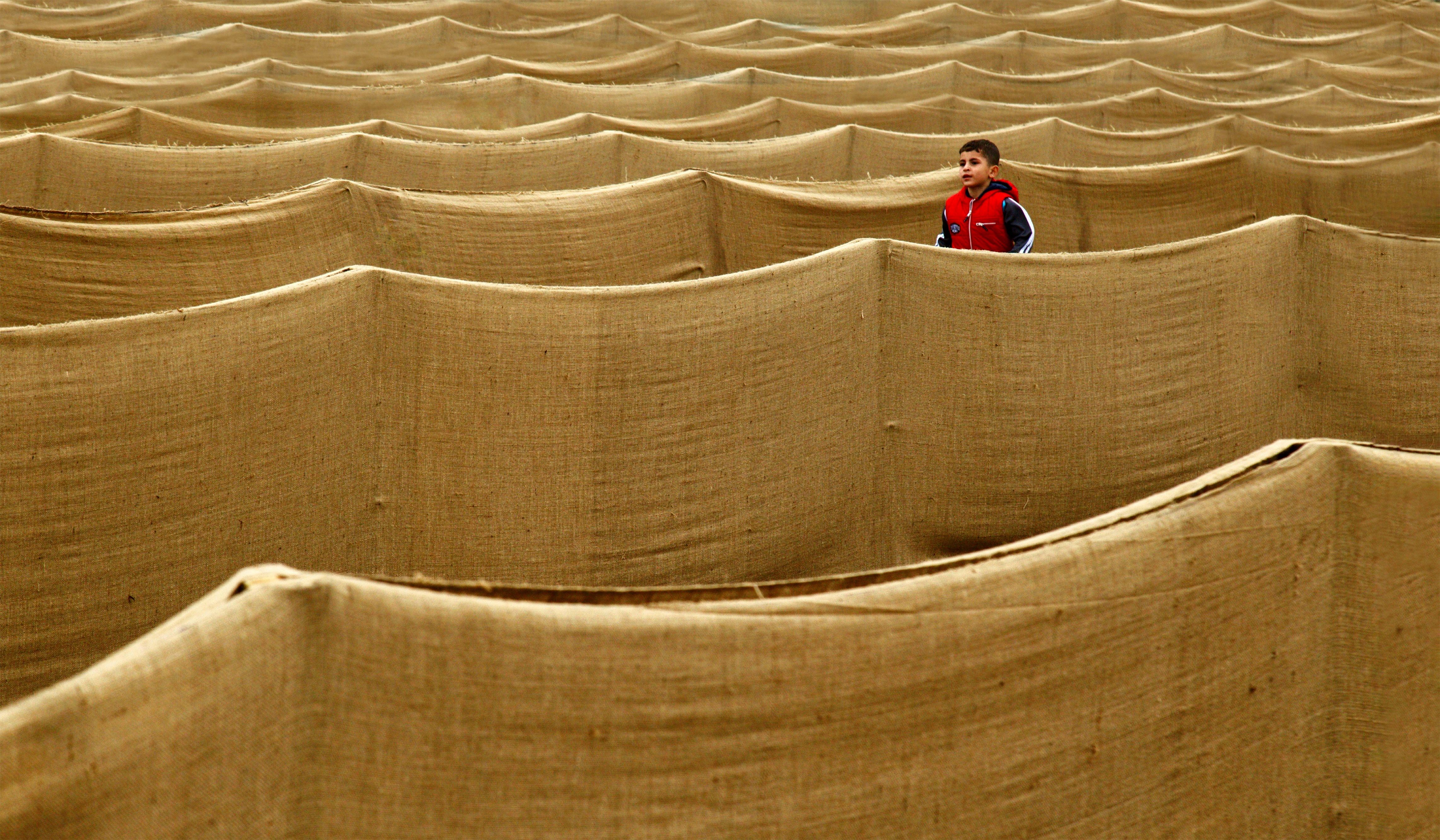 Photo of a Boy between Rows of Fabric · Free Stock Photo