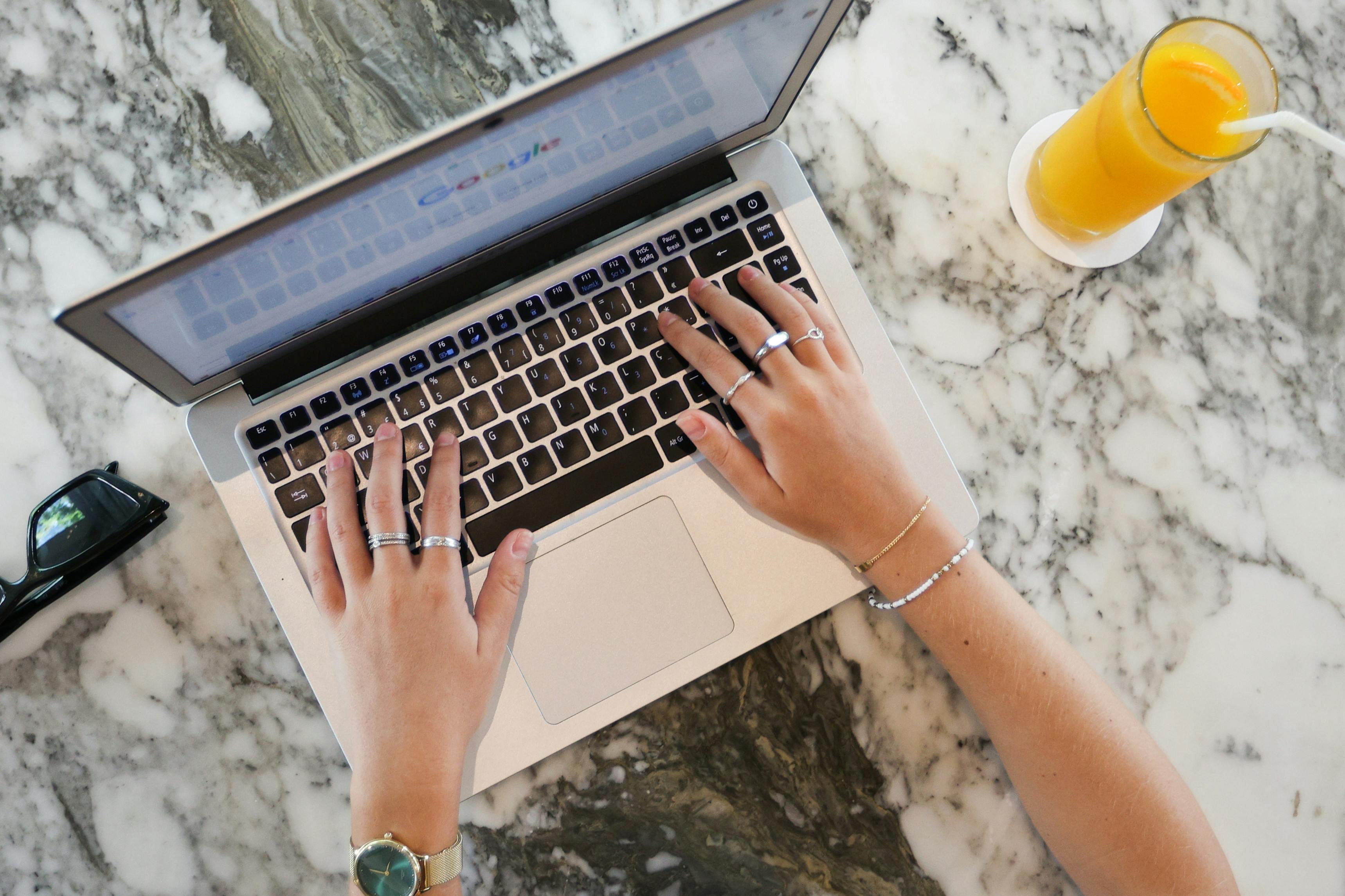 Close-up of woman typing on keyboard of laptop · Free Stock Photo