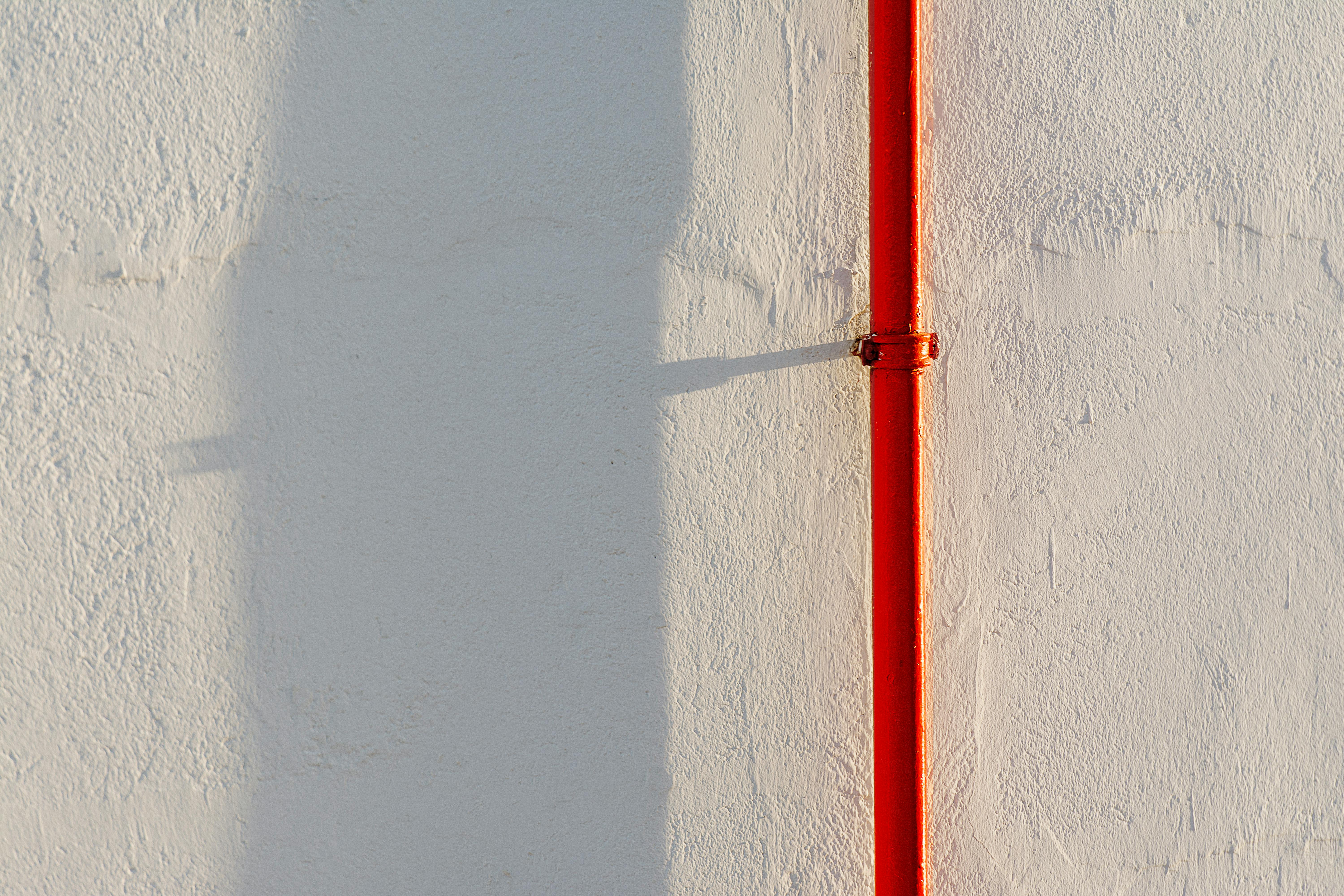 A Red Pipe Attached on the Concrete Wall · Free Stock Photo