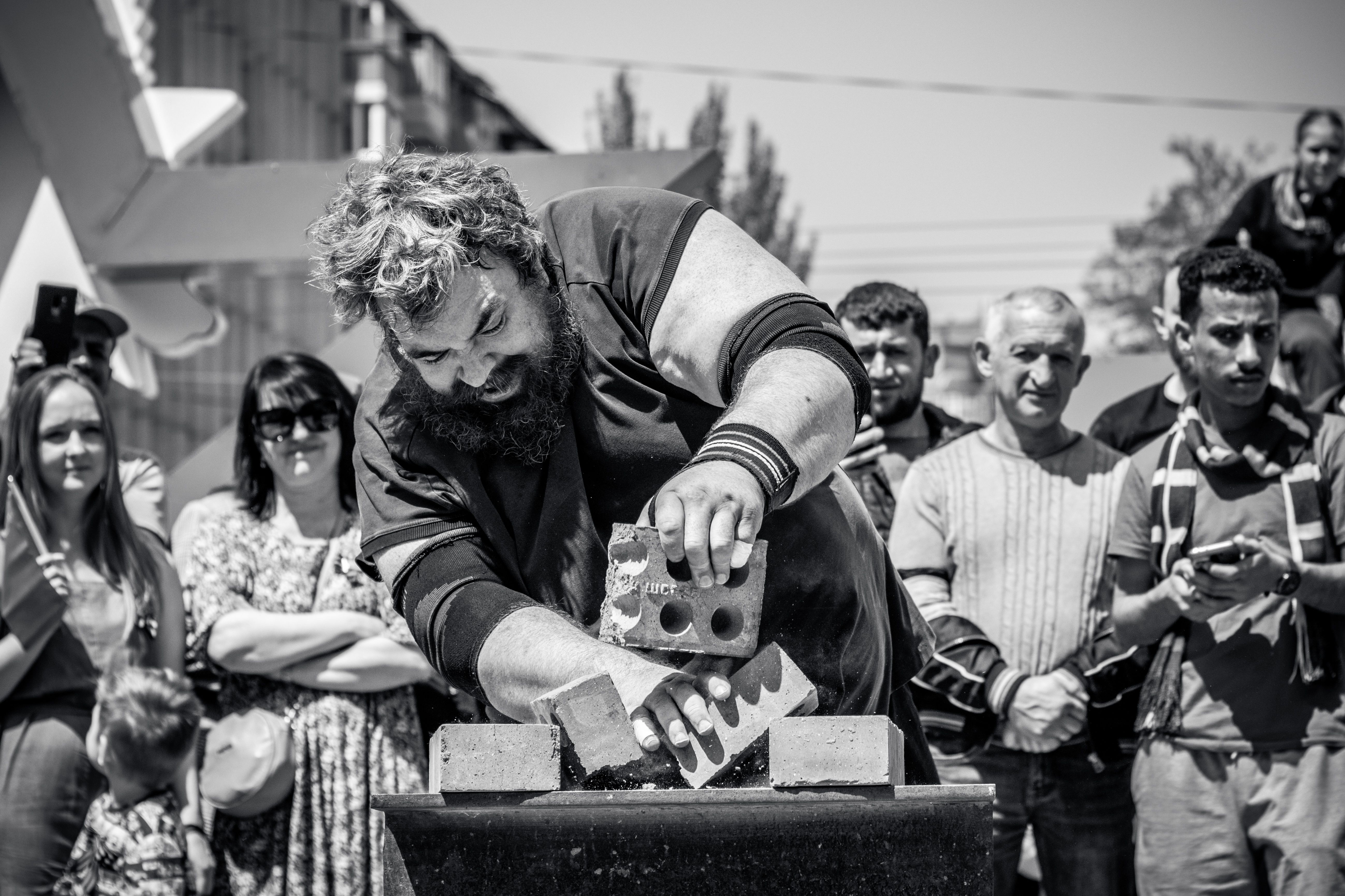 Black and White Photo of a Muscular Man Cracking Bricks and Crowd ...