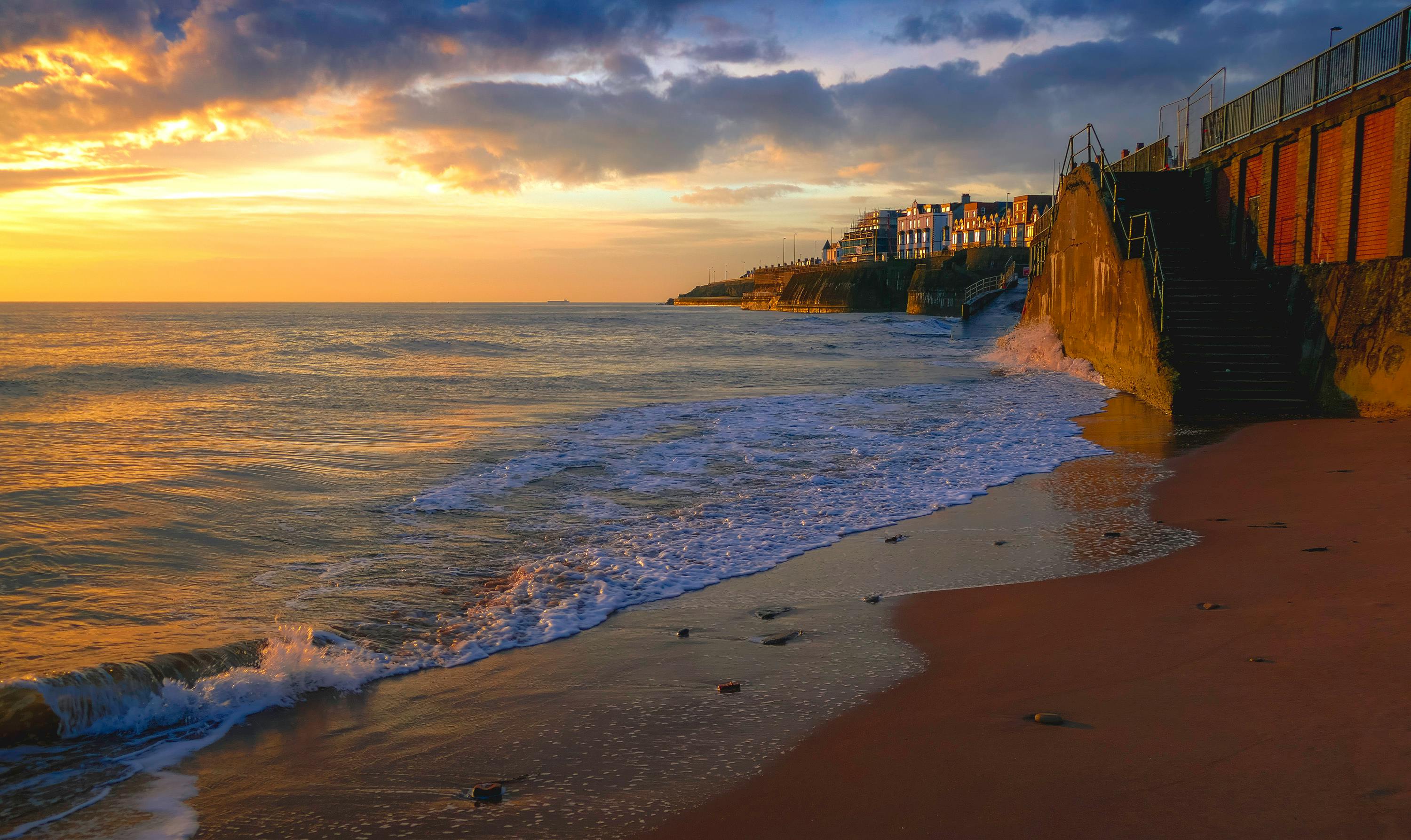 Brown Cliff Beside Ocean Under Blue Sky · Free Stock Photo