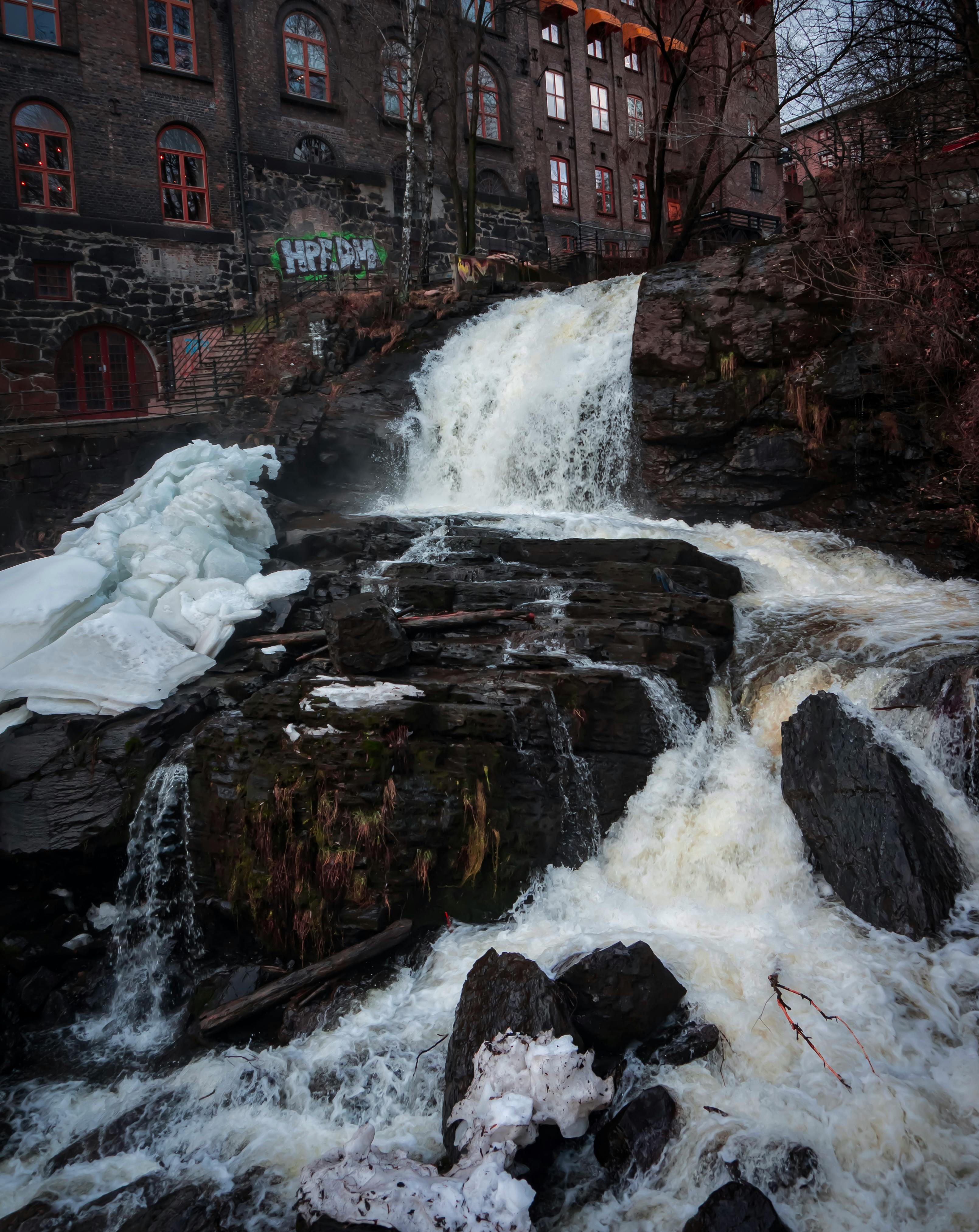 Waterfalls Beside a Brick Building · Free Stock Photo