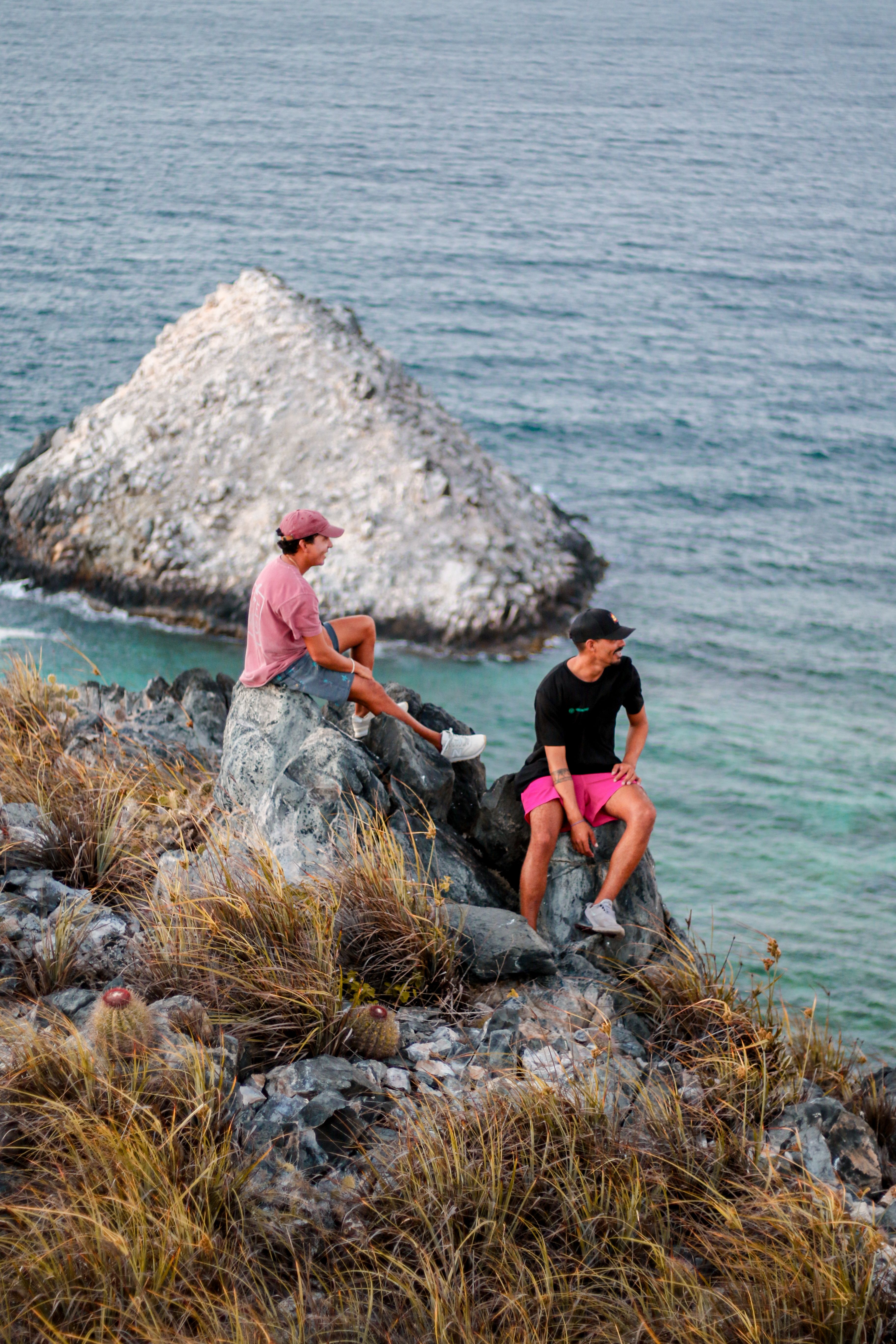 Woman and Man Resting on Rocks on Seashore · Free Stock Photo