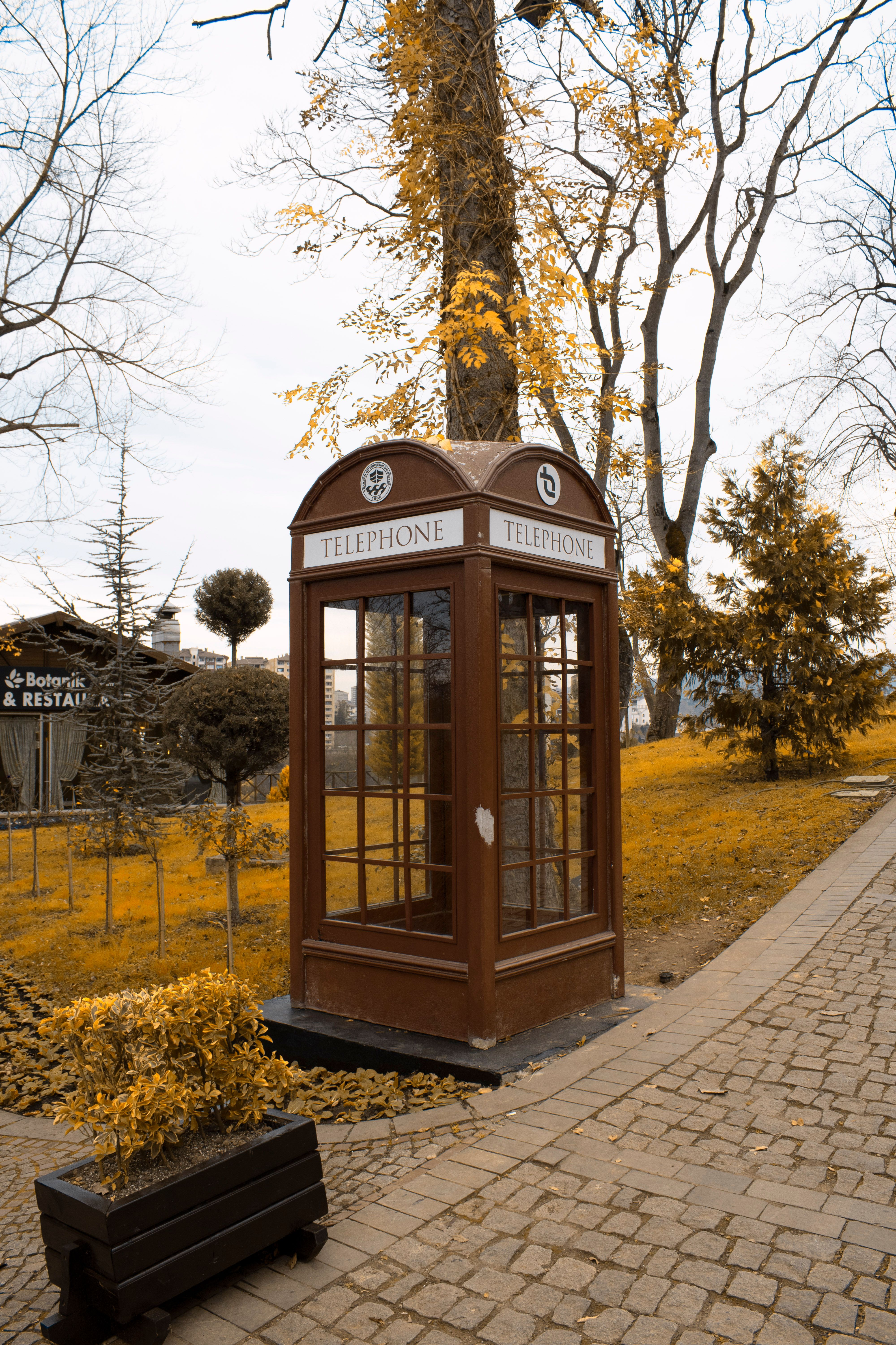 A Brown Telephone Booth Beside a Walkway Near Trees · Free Stock Photo