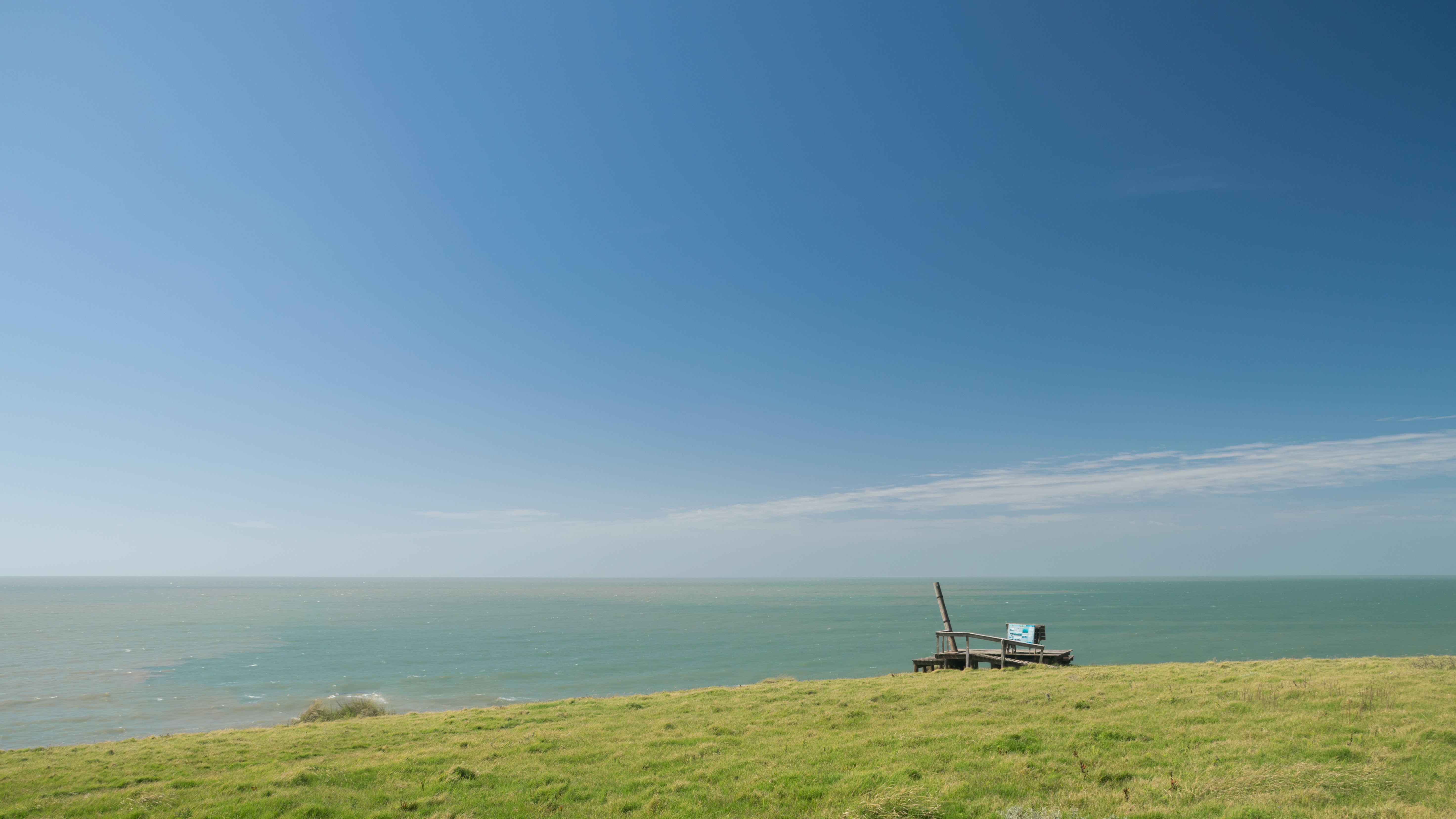 View of a Meadow and Sea under Blue Sky · Free Stock Photo
