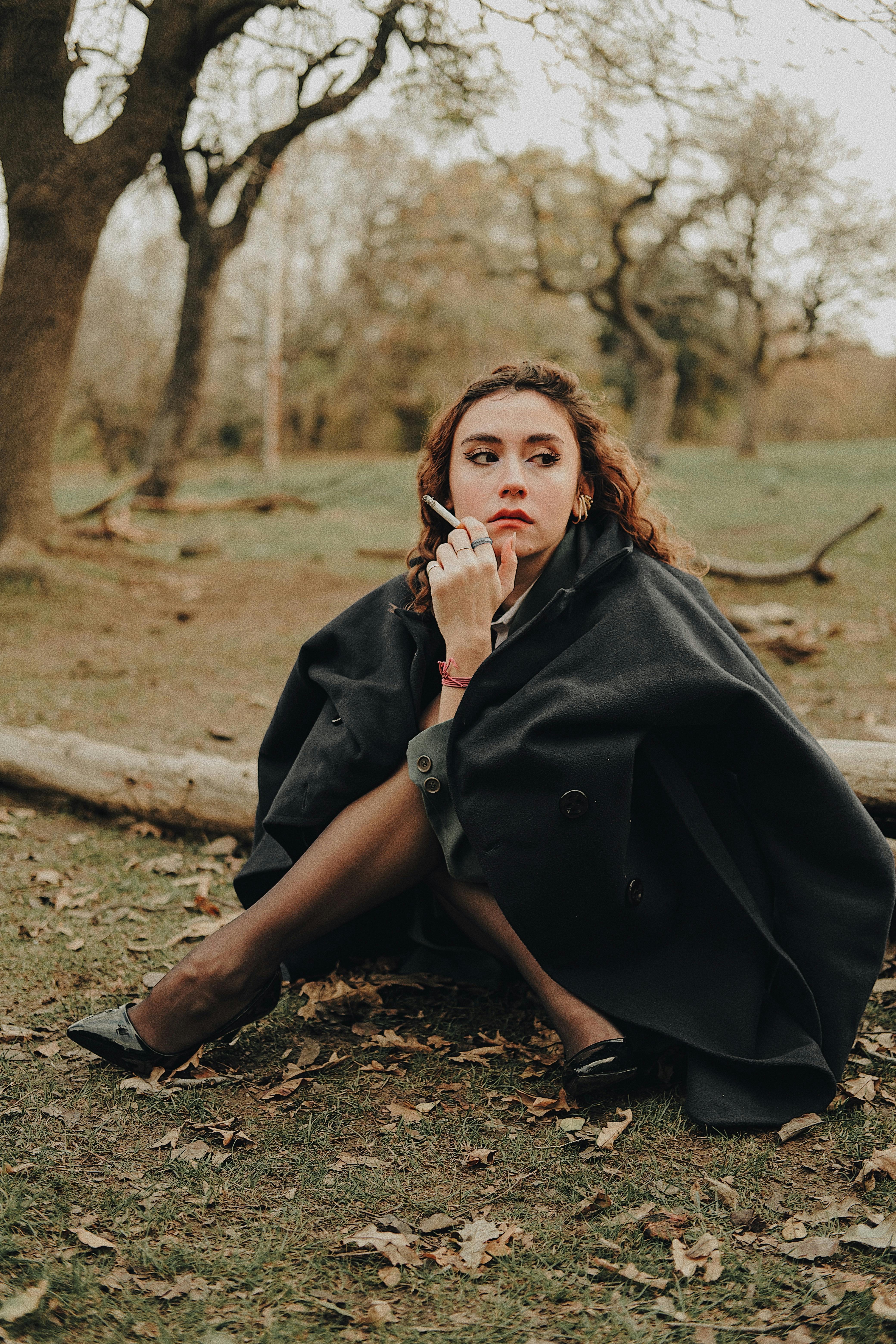 Young Woman Leaning against the Railing and Smoking a Cigarette · Free ...