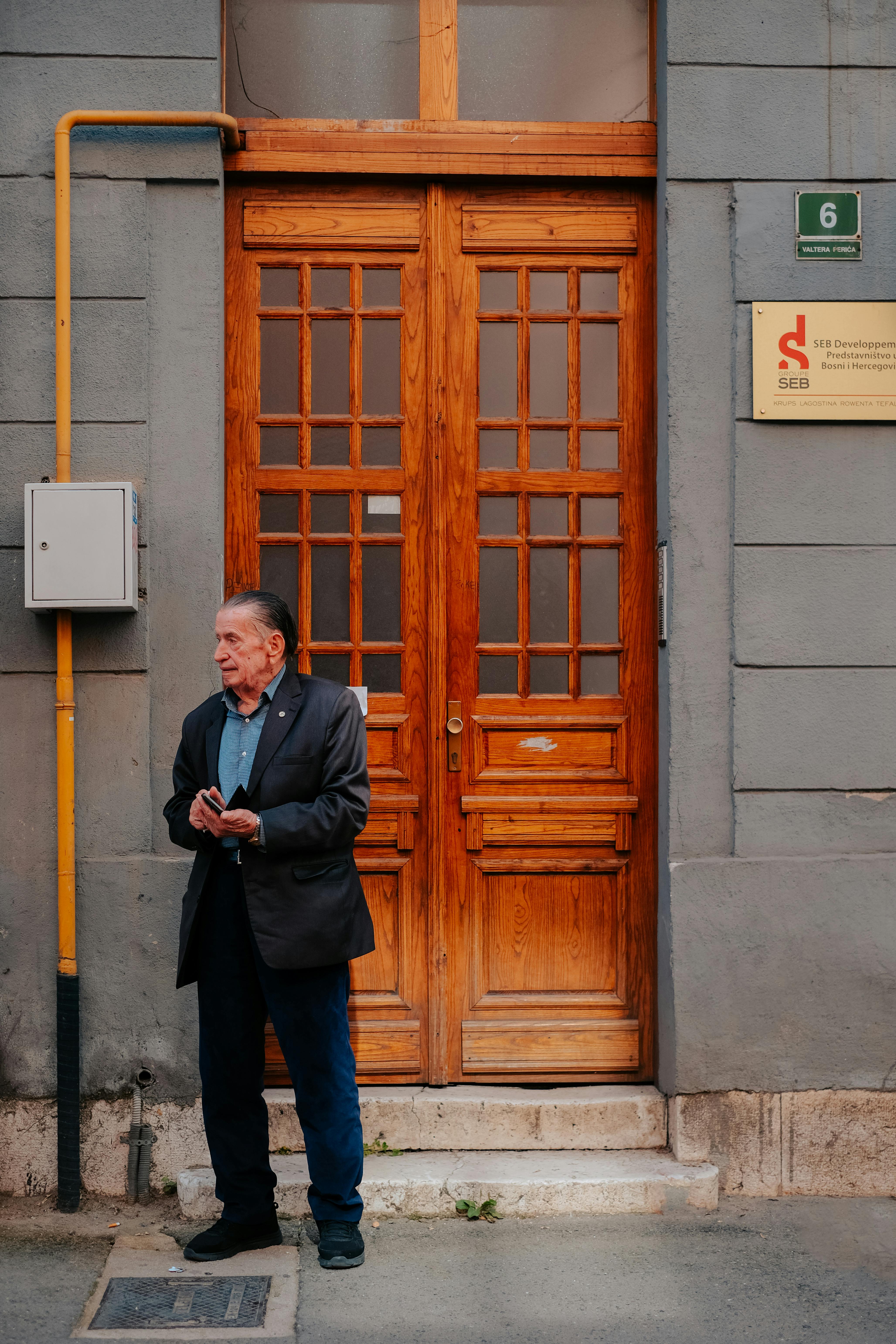 Old Man Standing near Building Wooden Doors · Free Stock Photo