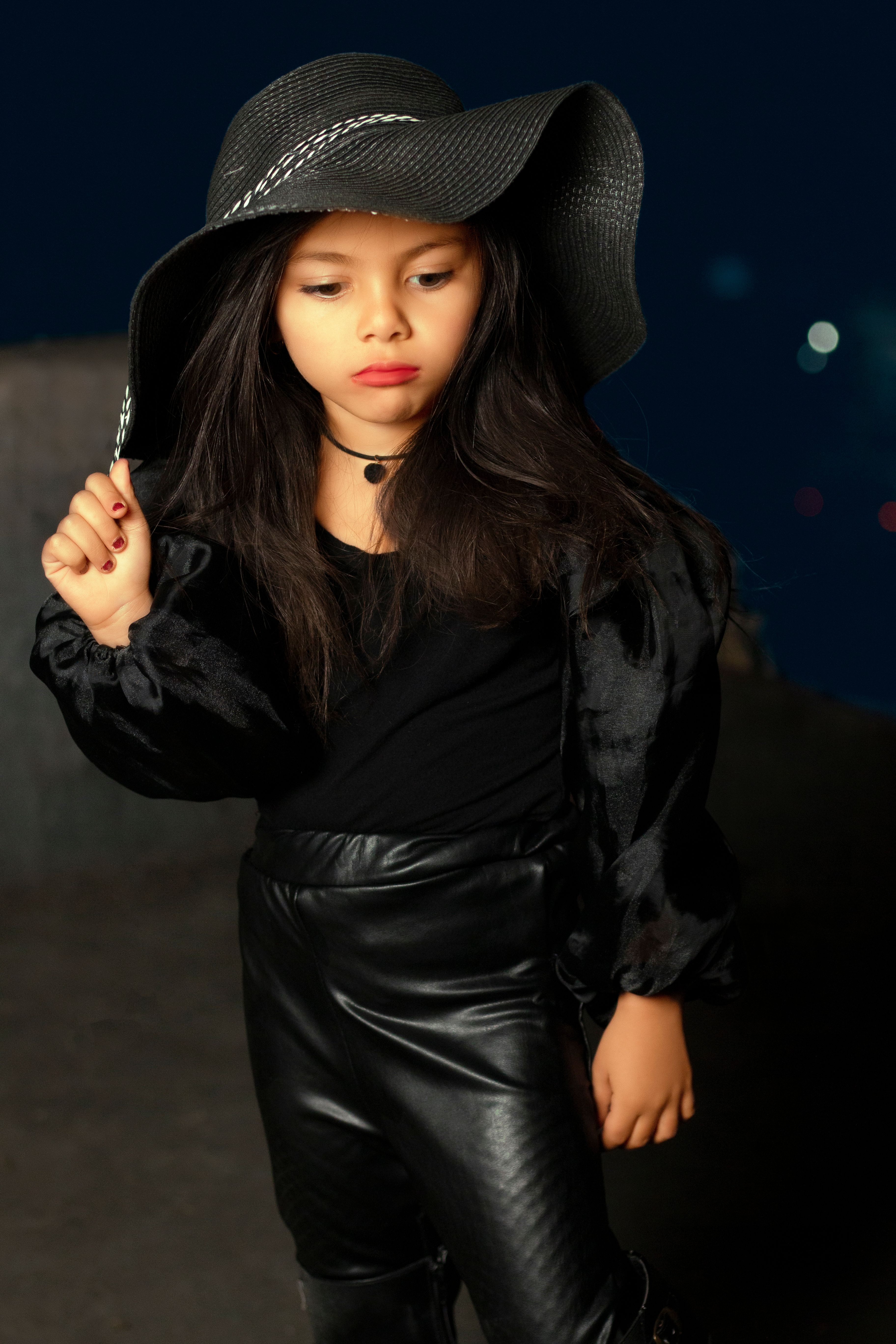 A little girl in leather pants and a hat · Free Stock Photo