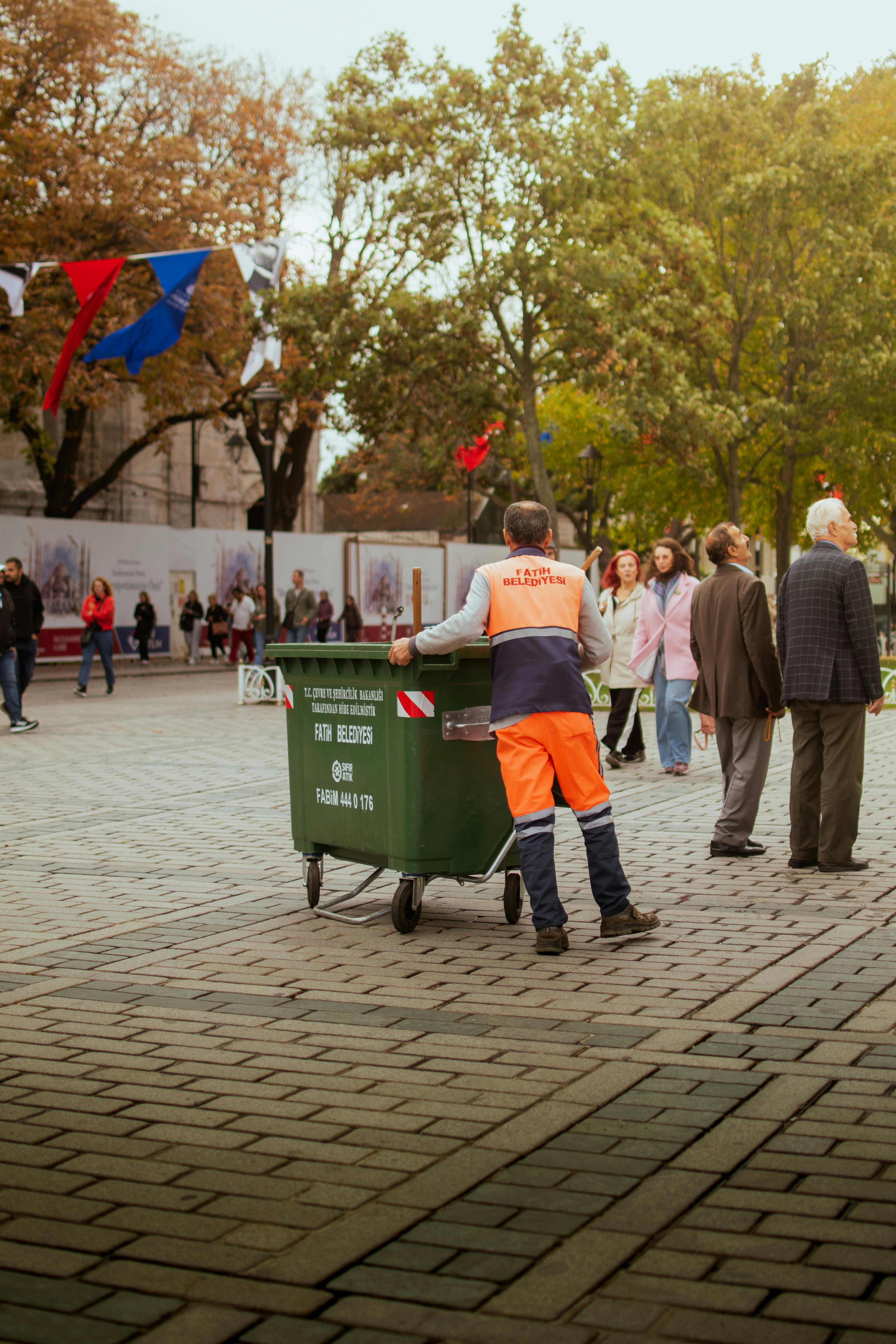 Male Worker Pulling a Garbage Bin · Free Stock Photo