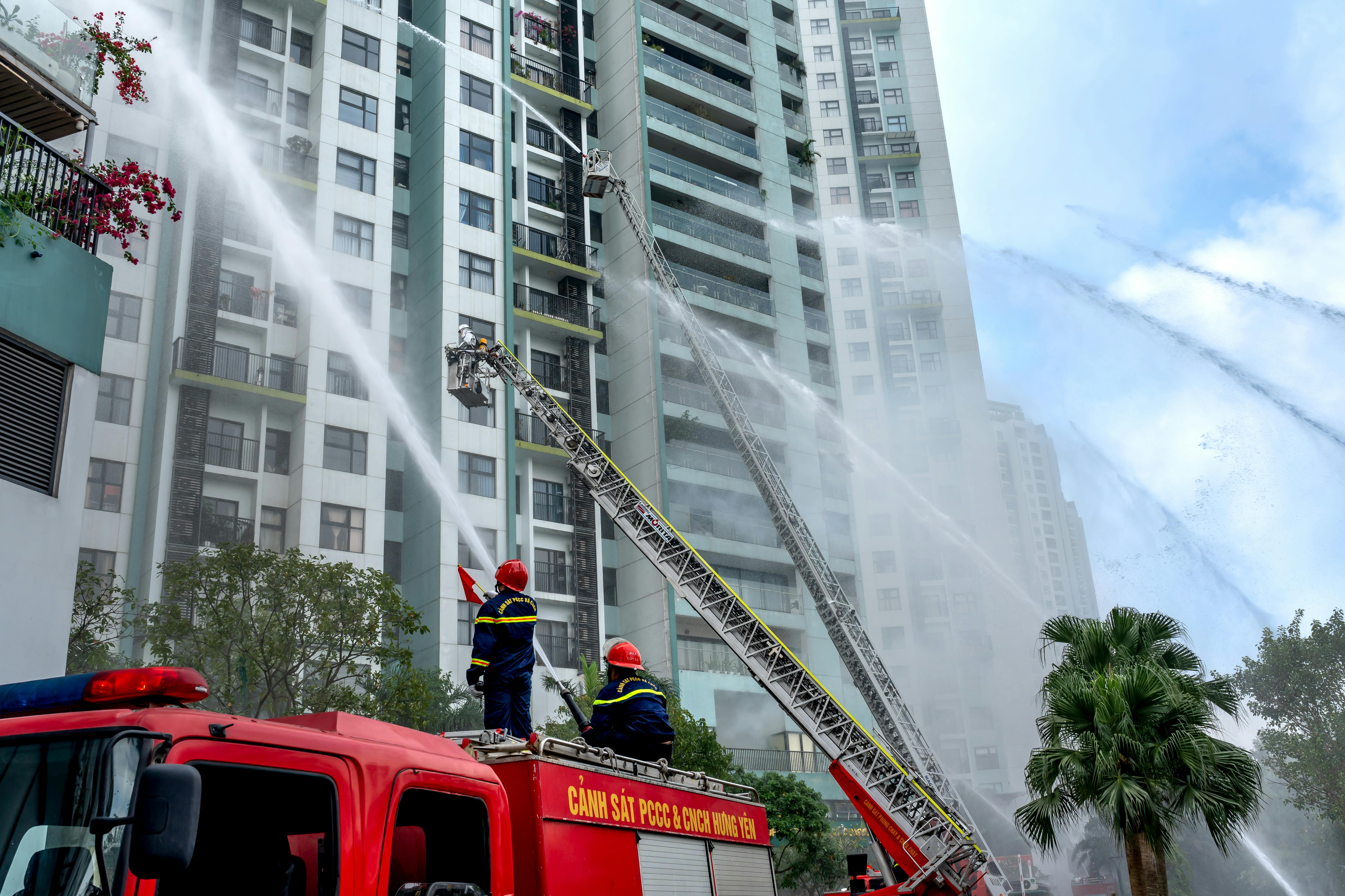 Firemen on Fire Trucks Spraying Water on a High Rises Buildings · Free ...