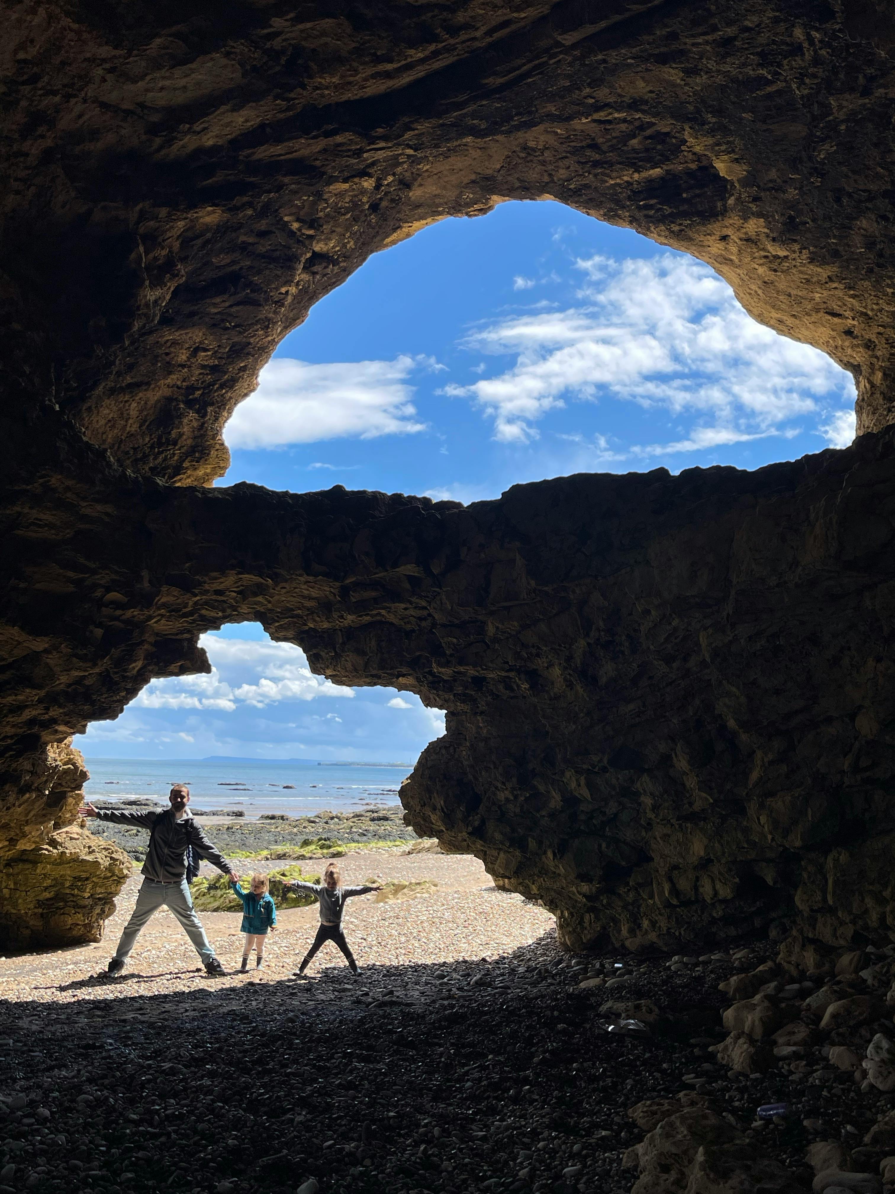 Father with Children Posing in Cave on Seashore · Free Stock Photo