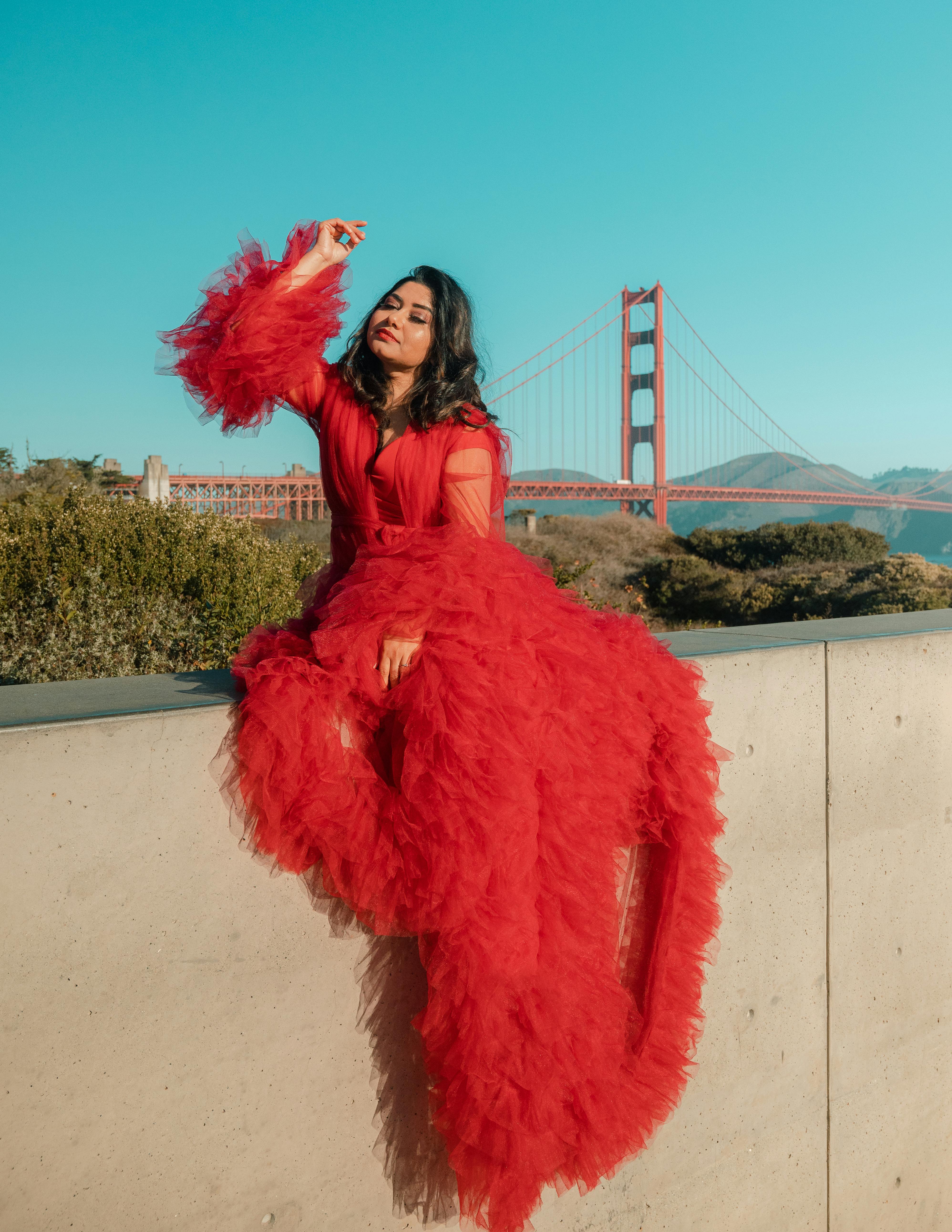 Brunette Woman in Red Dress Sitting with Golden Gate behind · Free ...
