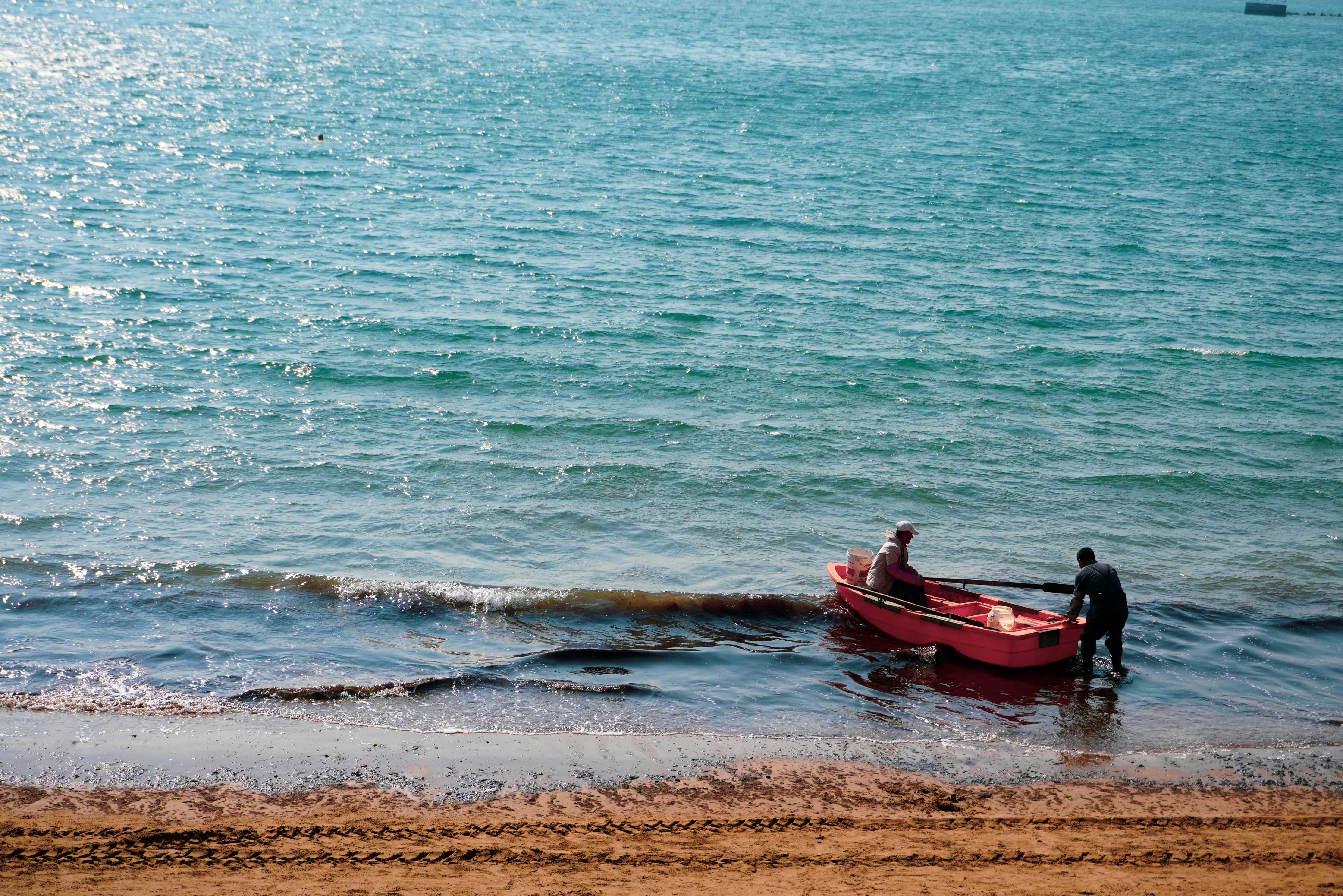 Men Pushing a Boat from the Shore into the Sea · Free Stock Photo