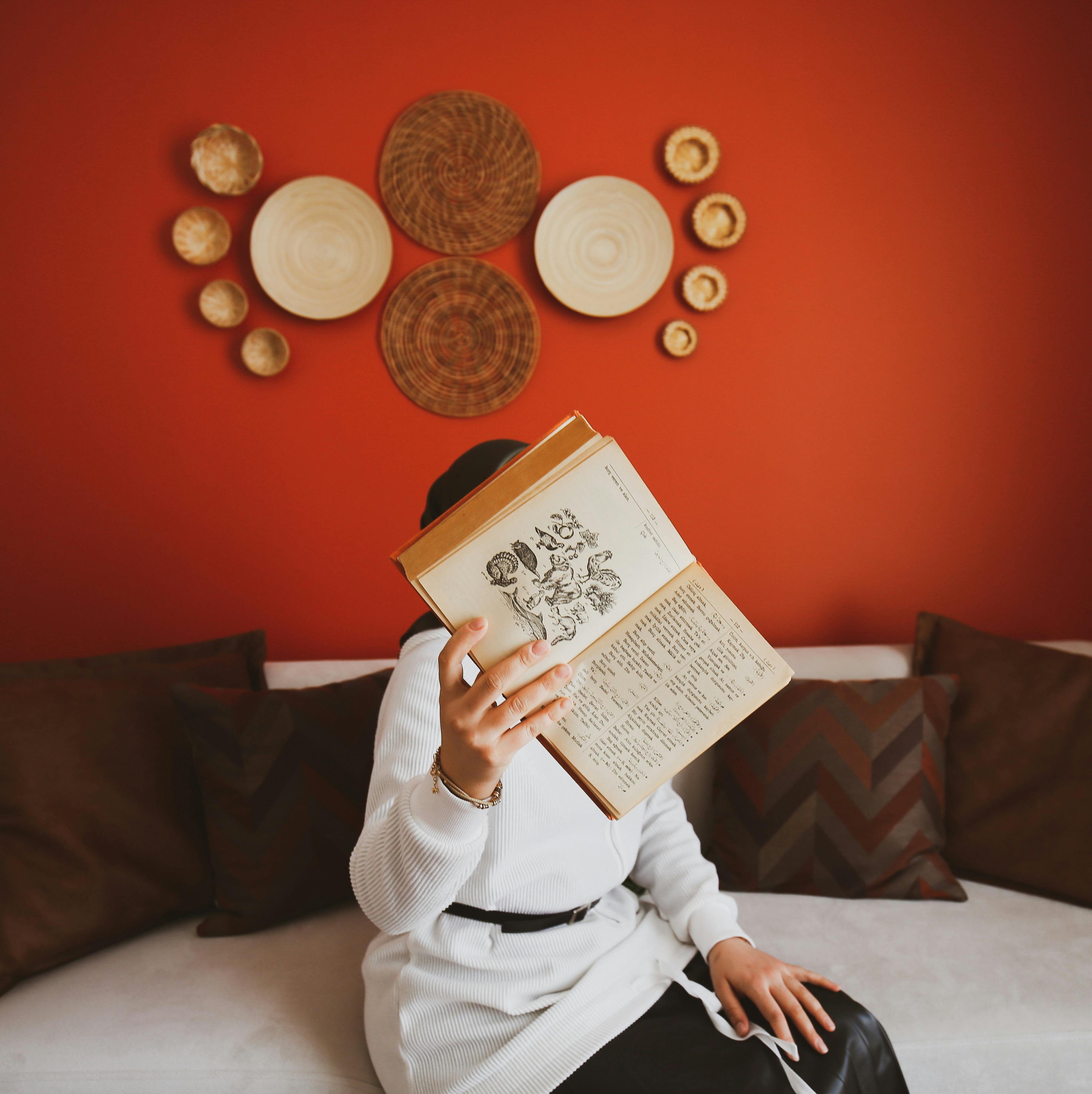 Woman Sitting on a Sofa and Holding an Open Book · Free Stock Photo
