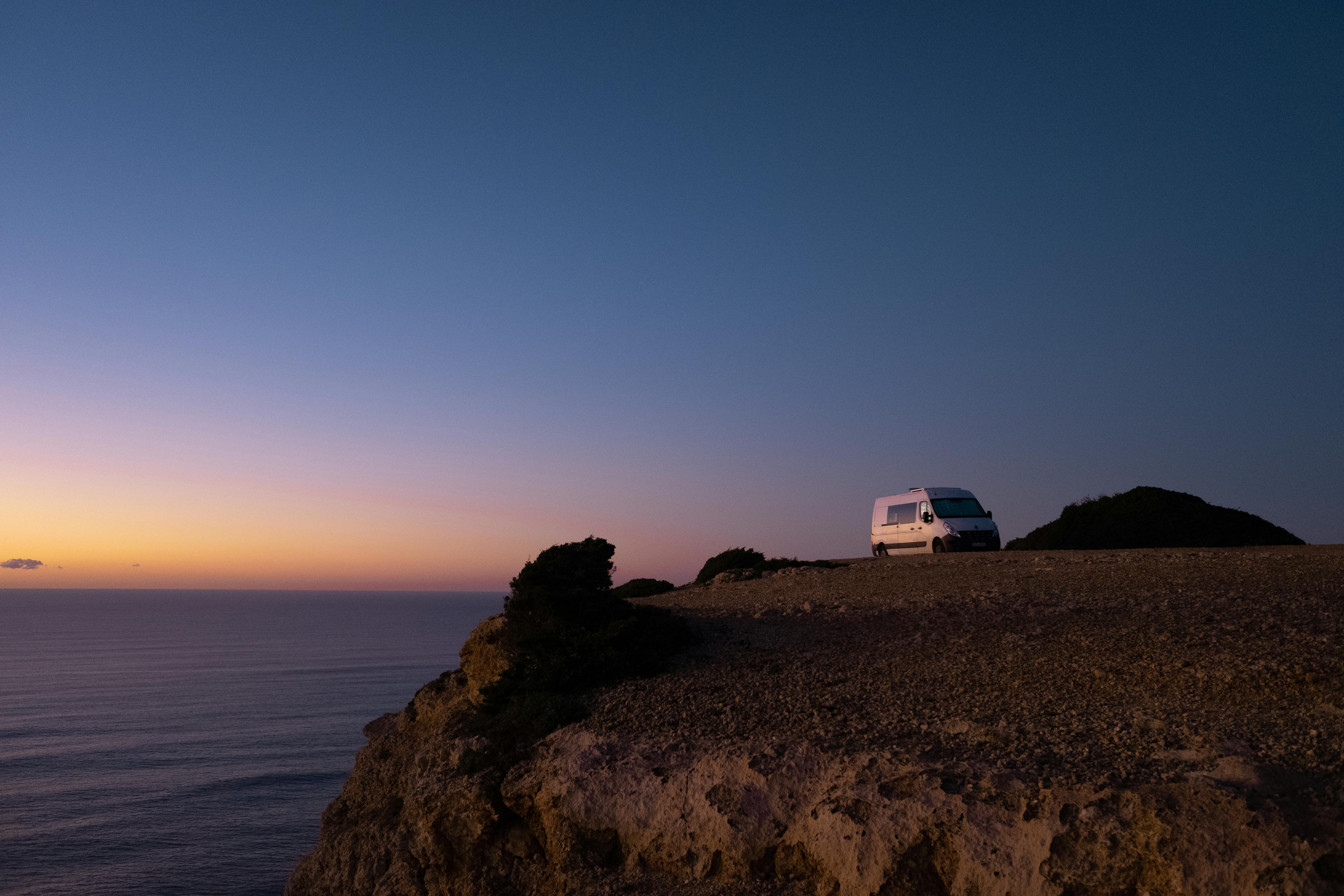 A Campervan Parked on a Cliff During Evening Sky · Free Stock Photo