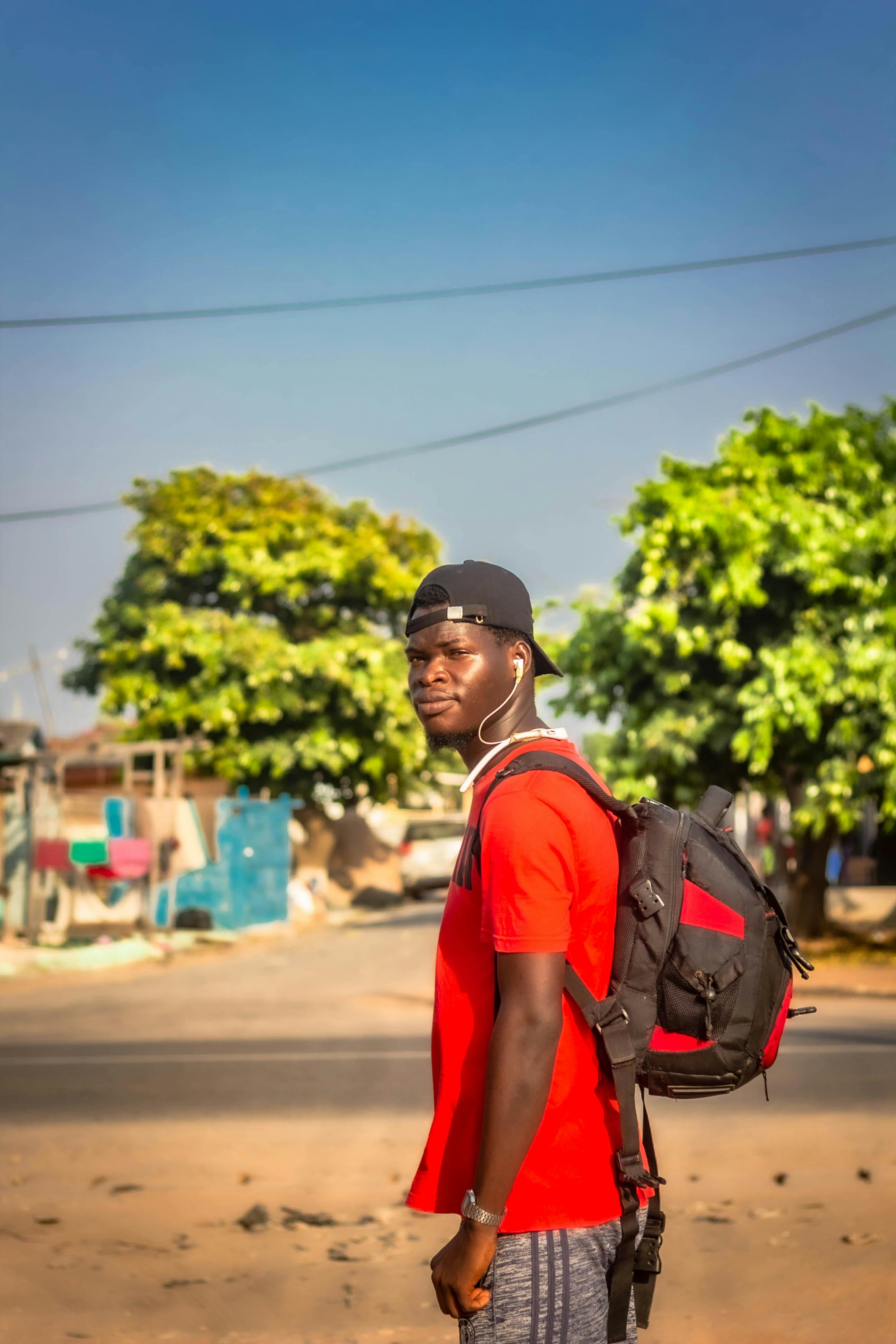 Side View of a Man in an Orange Shirt Wearing a Backpack · Free Stock Photo