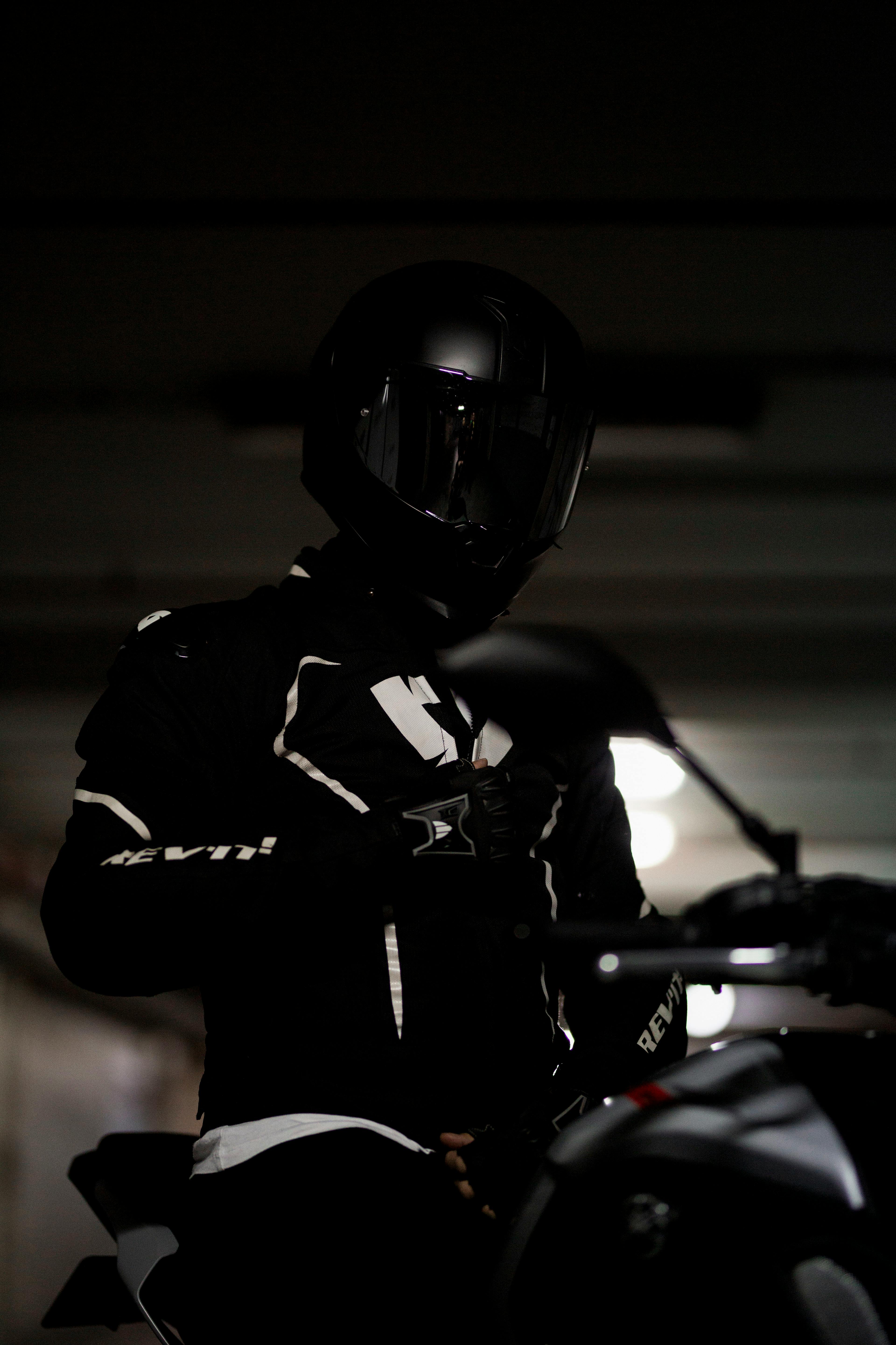 Man in All Black Motorcycle Attire Standing by the Vehicle in a Parking ...