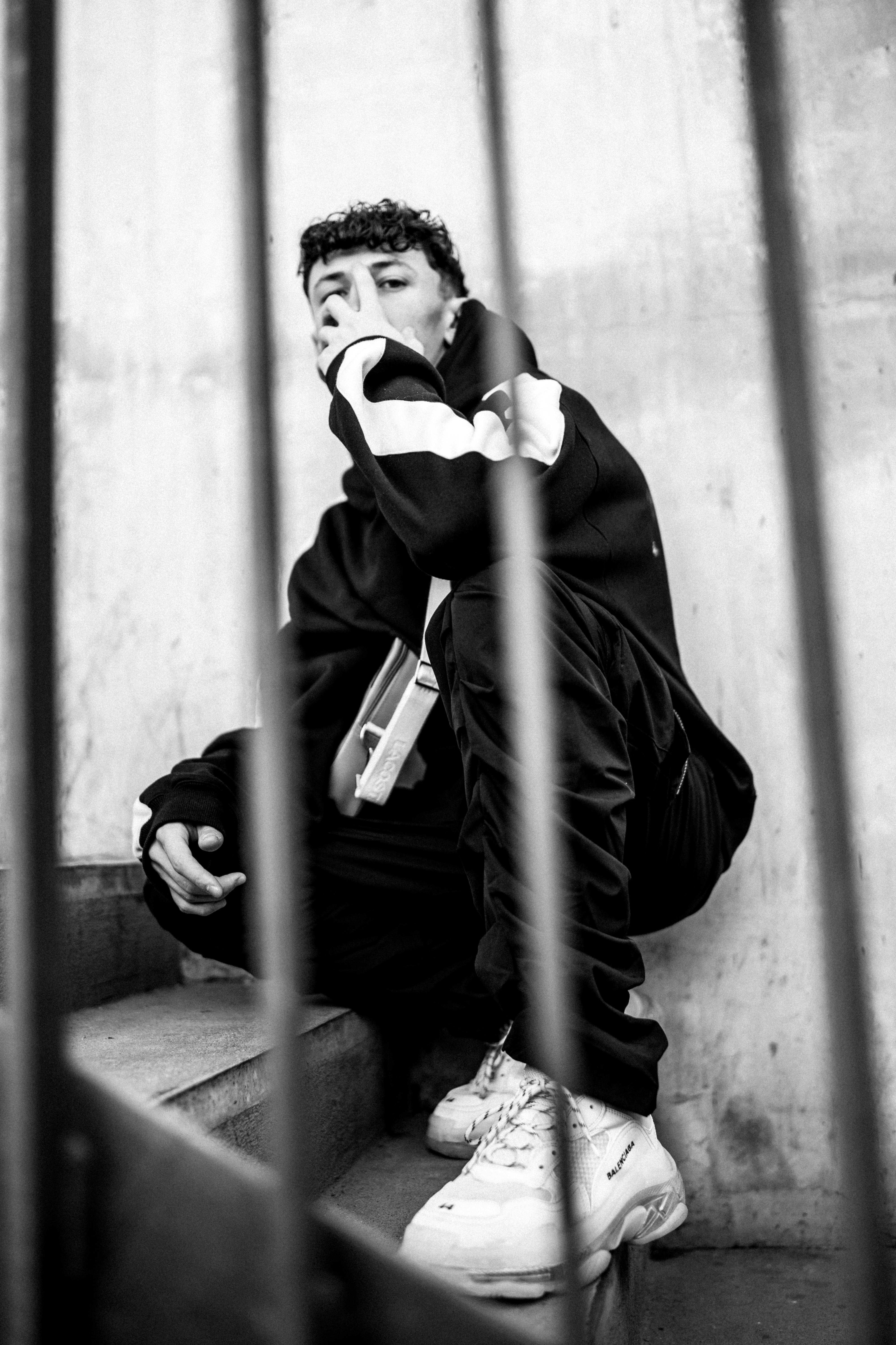 Young Man in a Casual Trendy Outfit Crouching on Steps · Free Stock Photo