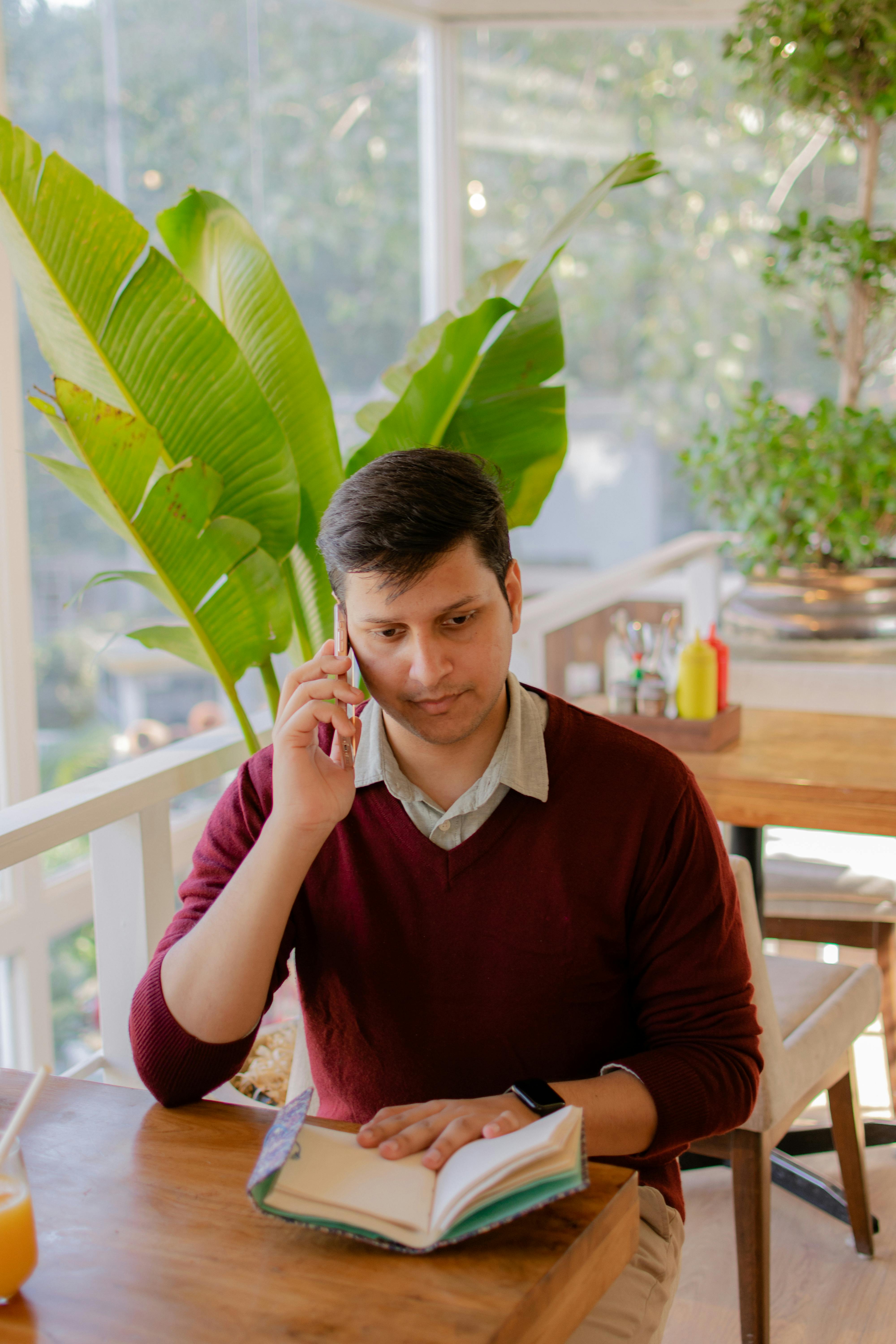 Man Sitting in a Restaurant and Making a Phone Call · Free Stock Photo