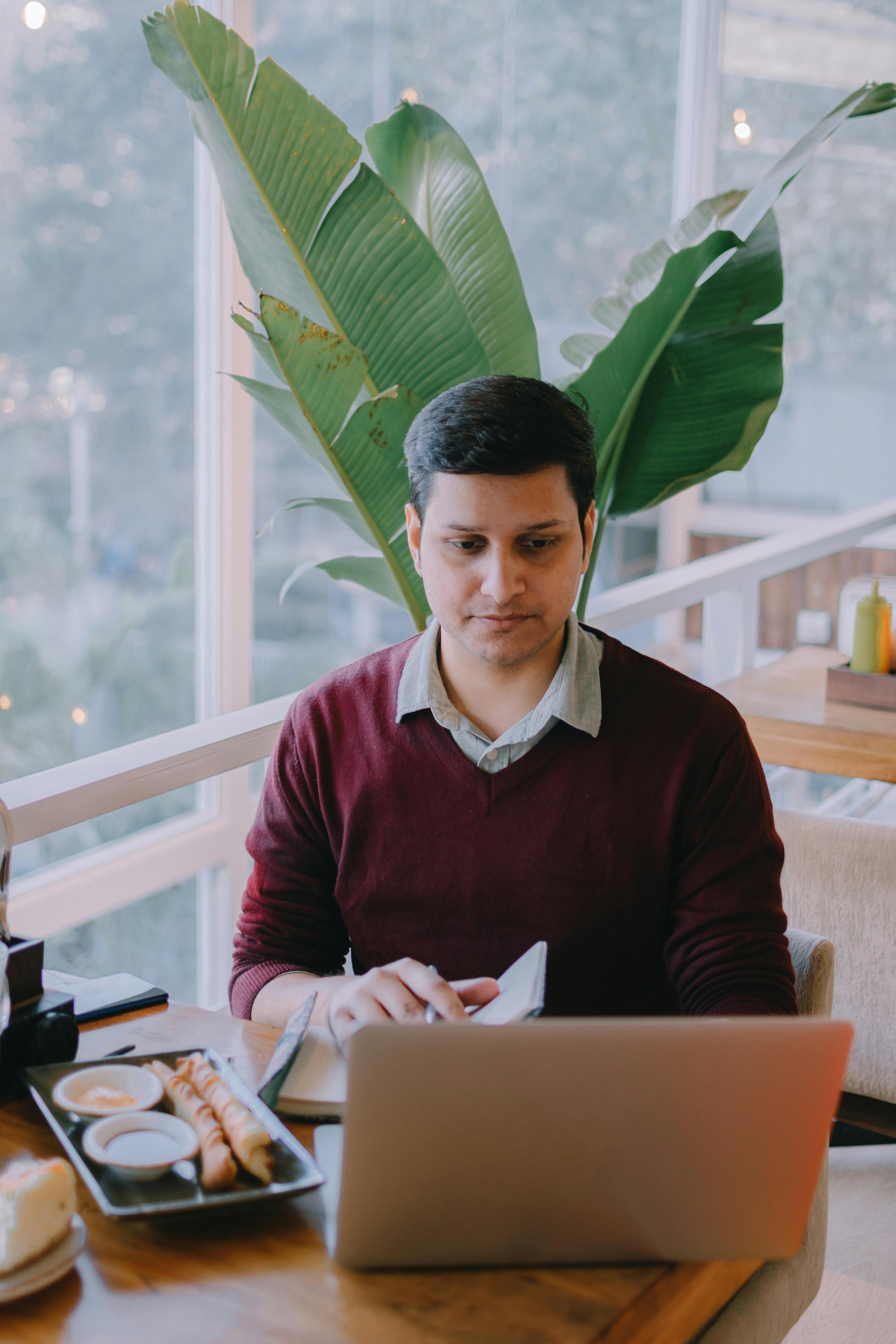 Man Sitting by Table with Laptop · Free Stock Photo