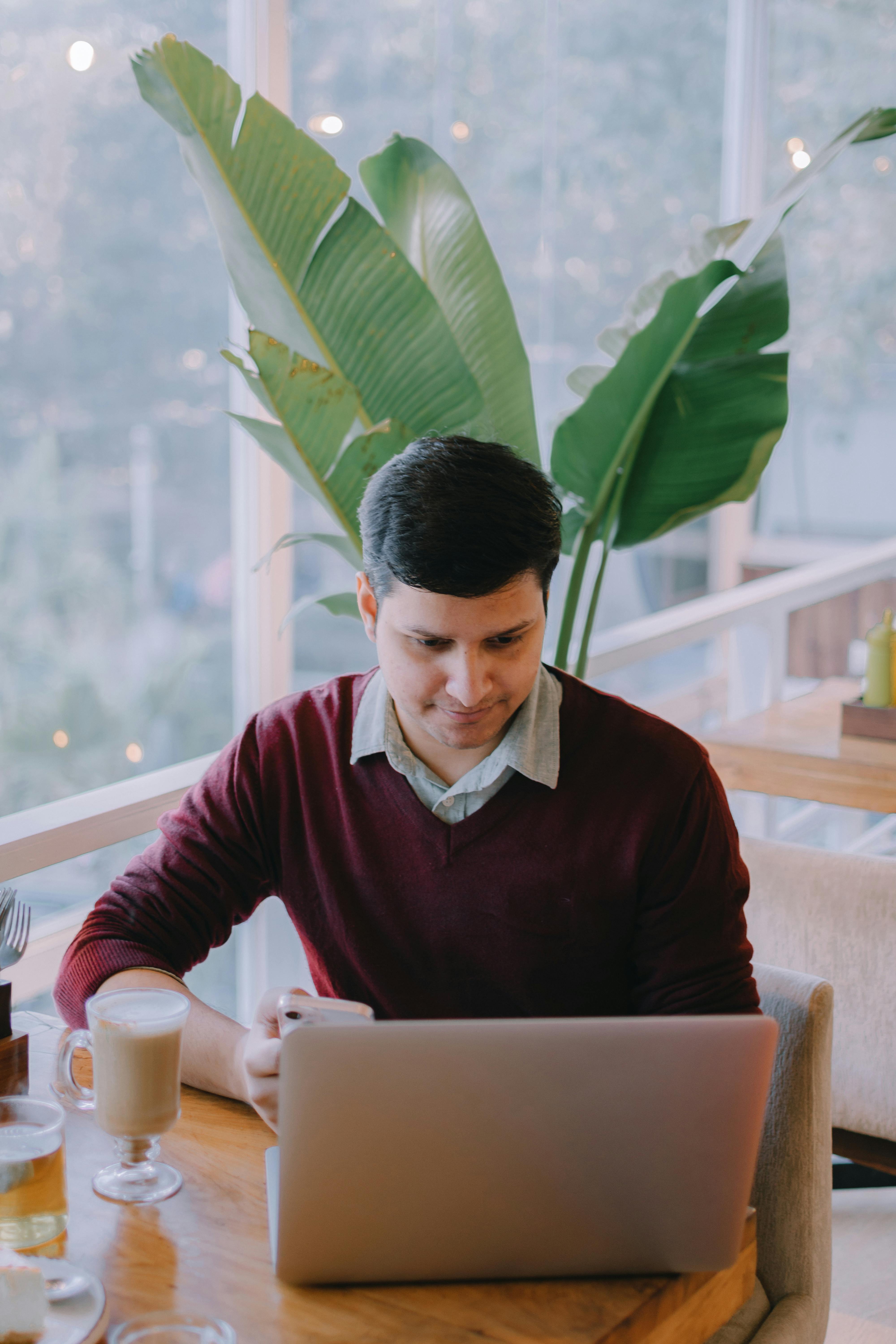 Man Sitting by Table with Laptop · Free Stock Photo