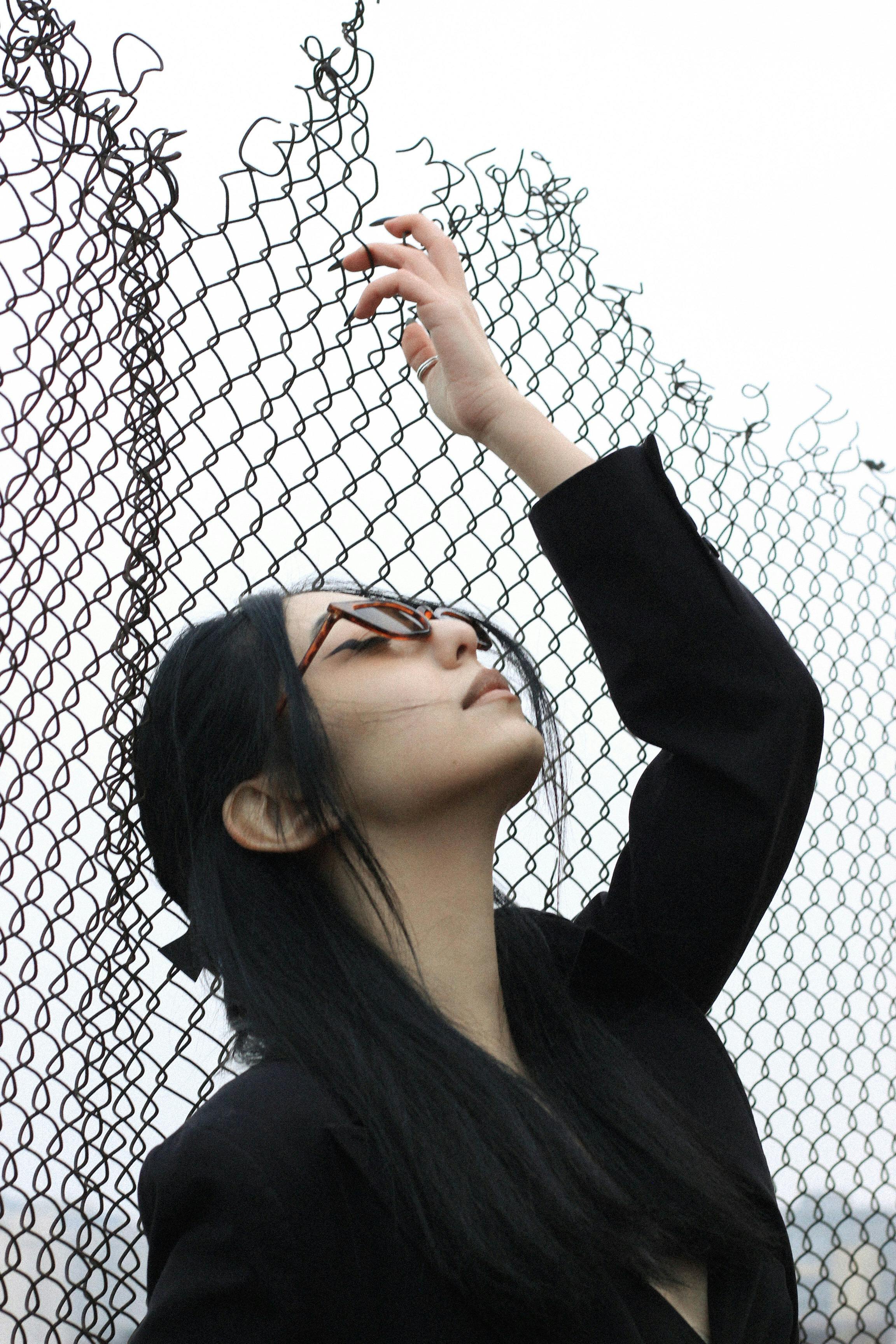 Man Leaning on Chain Link Fence · Free Stock Photo