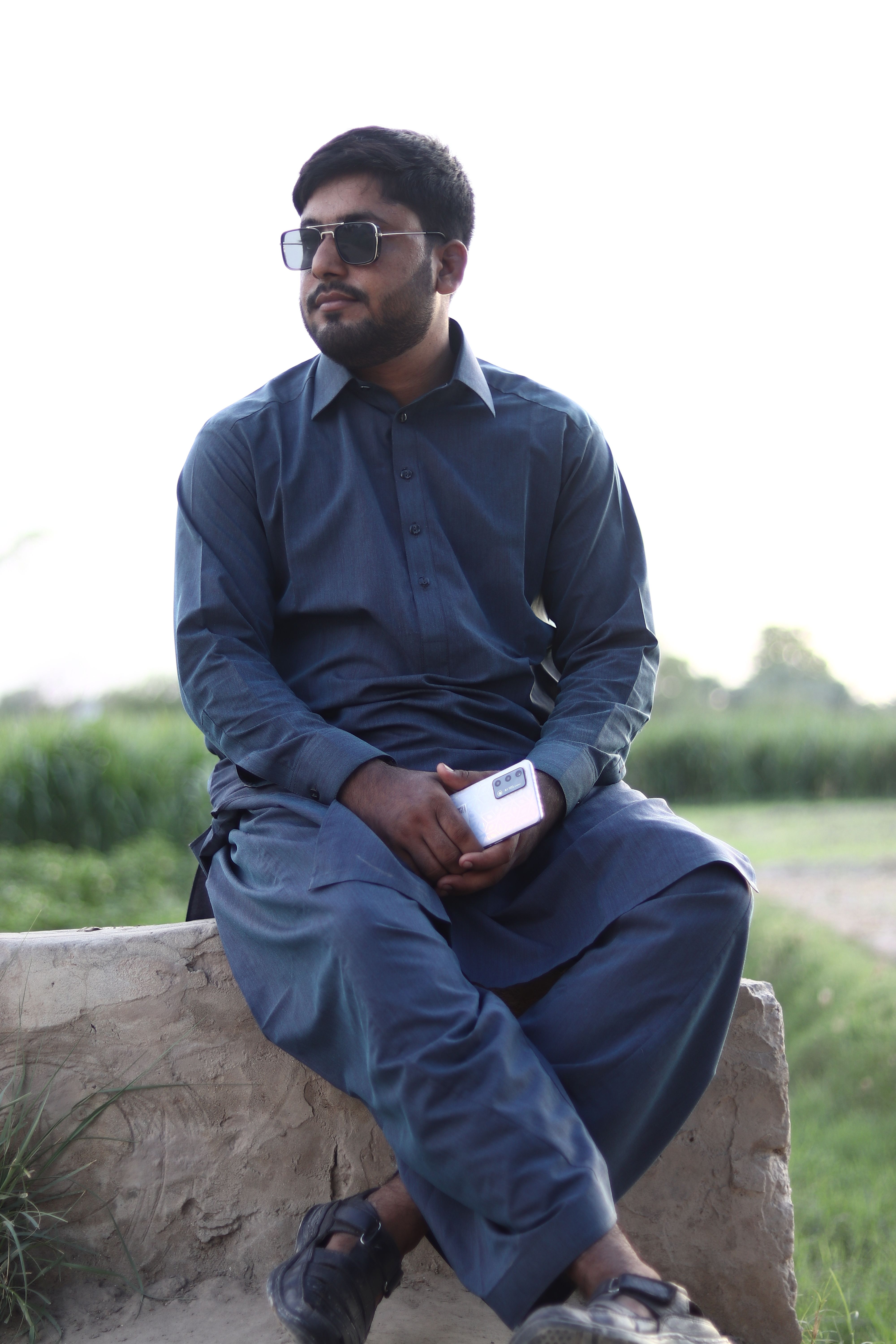 Man in Traditional Clothing Sitting Outdoors in Summer · Free Stock Photo