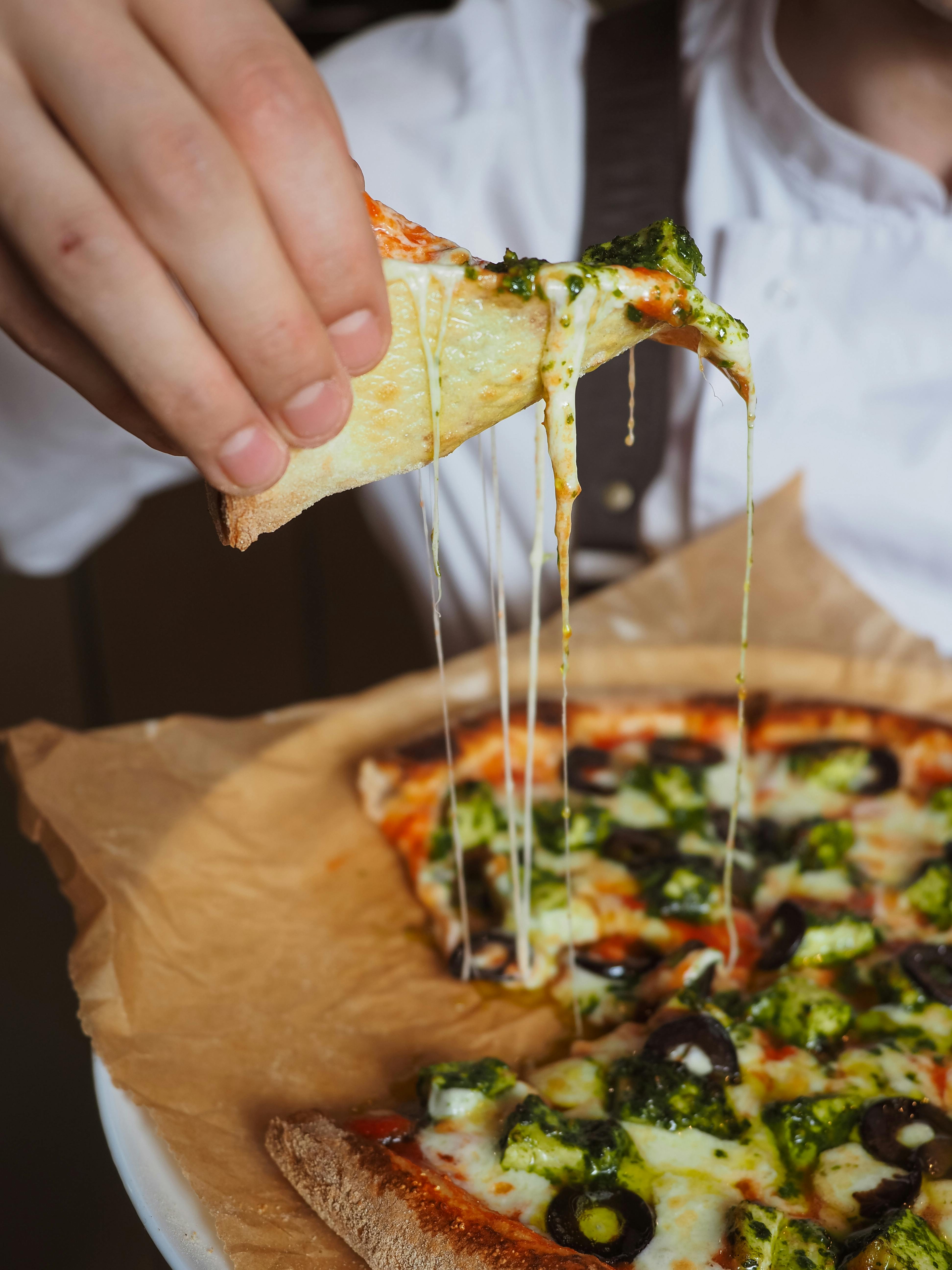 A Hand Holding a Piece of Pizza · Free Stock Photo