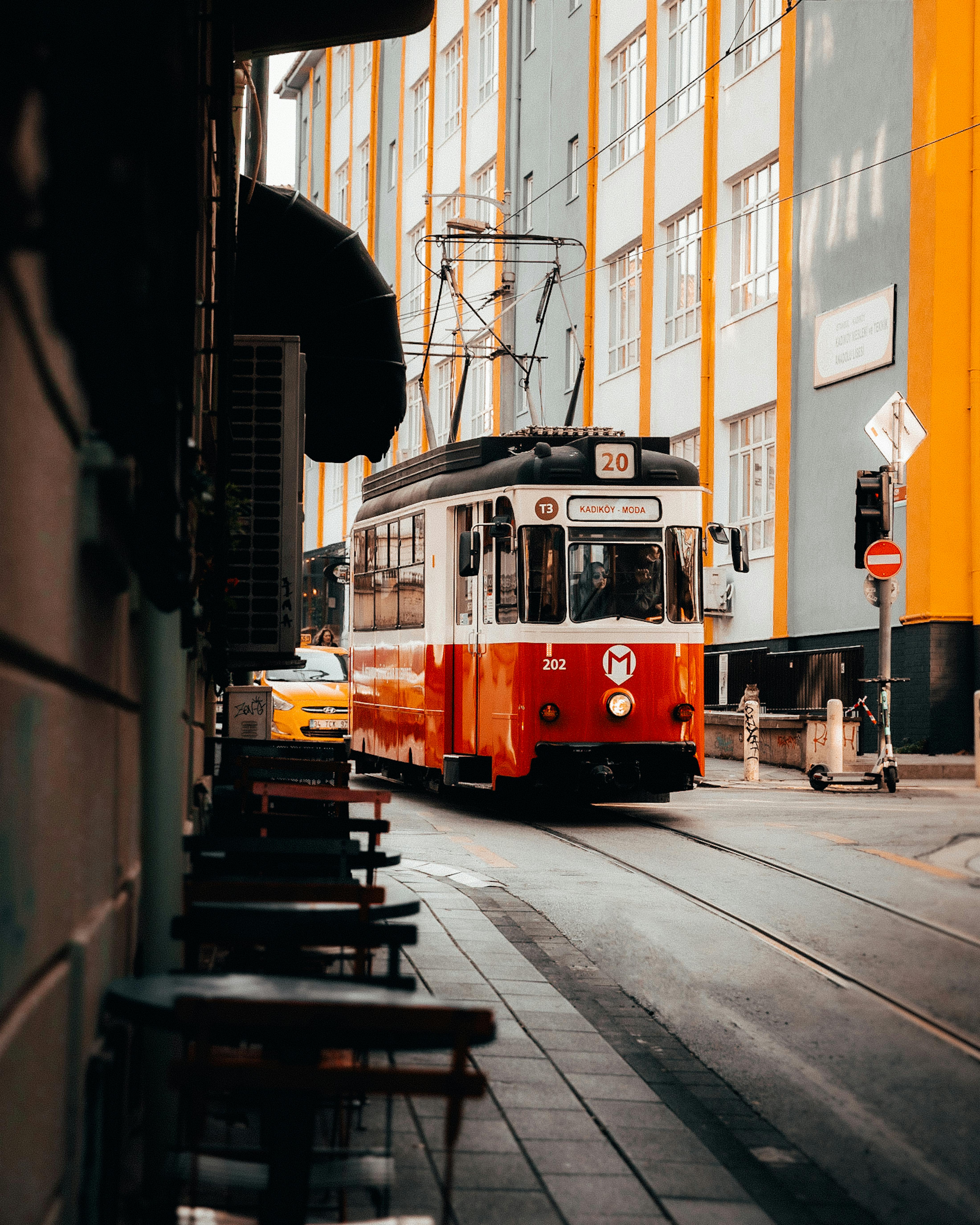 Red Tram Passing Between Concrete Buildings · Free Stock Photo