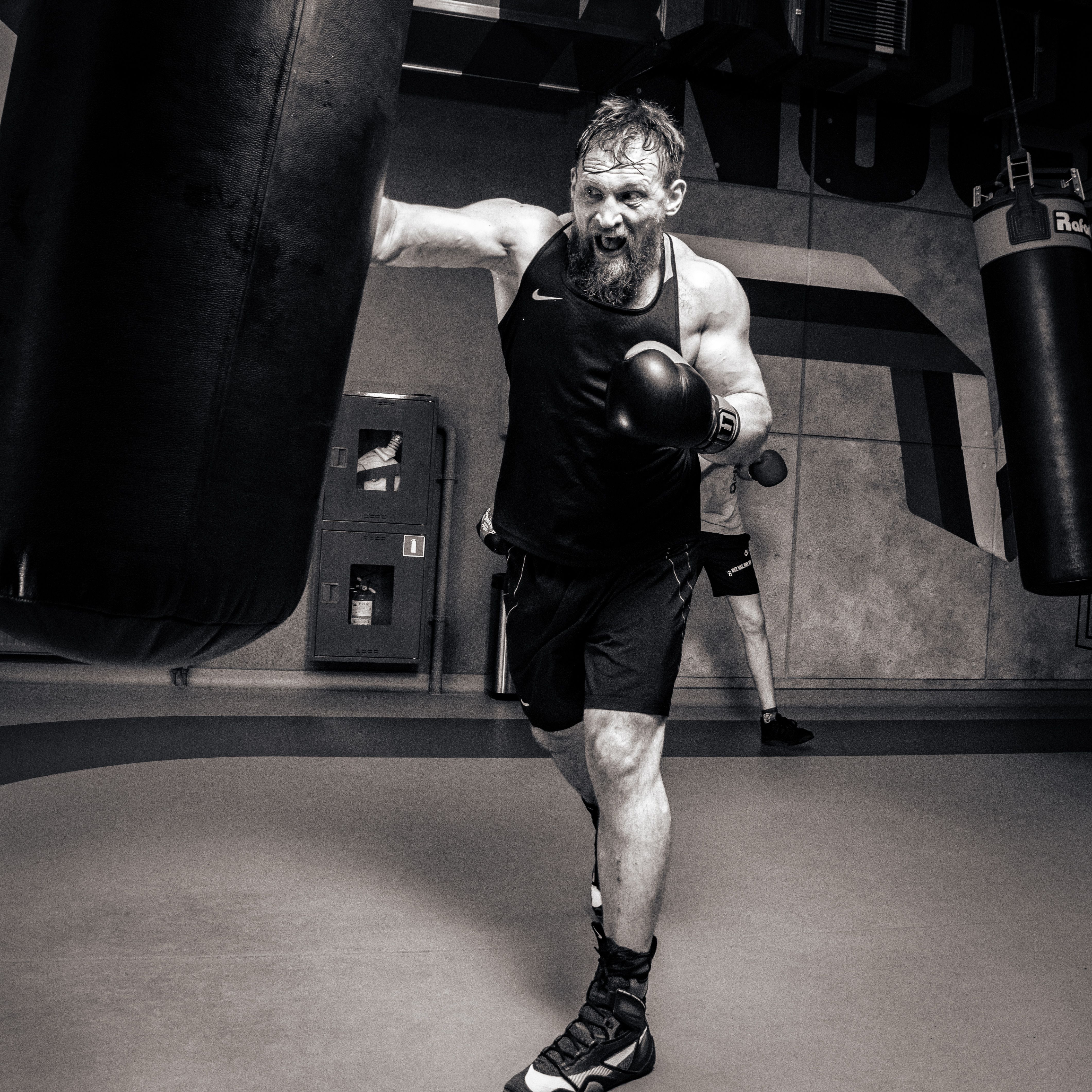 A Grayscale of Man Punching a Punching Bag · Free Stock Photo