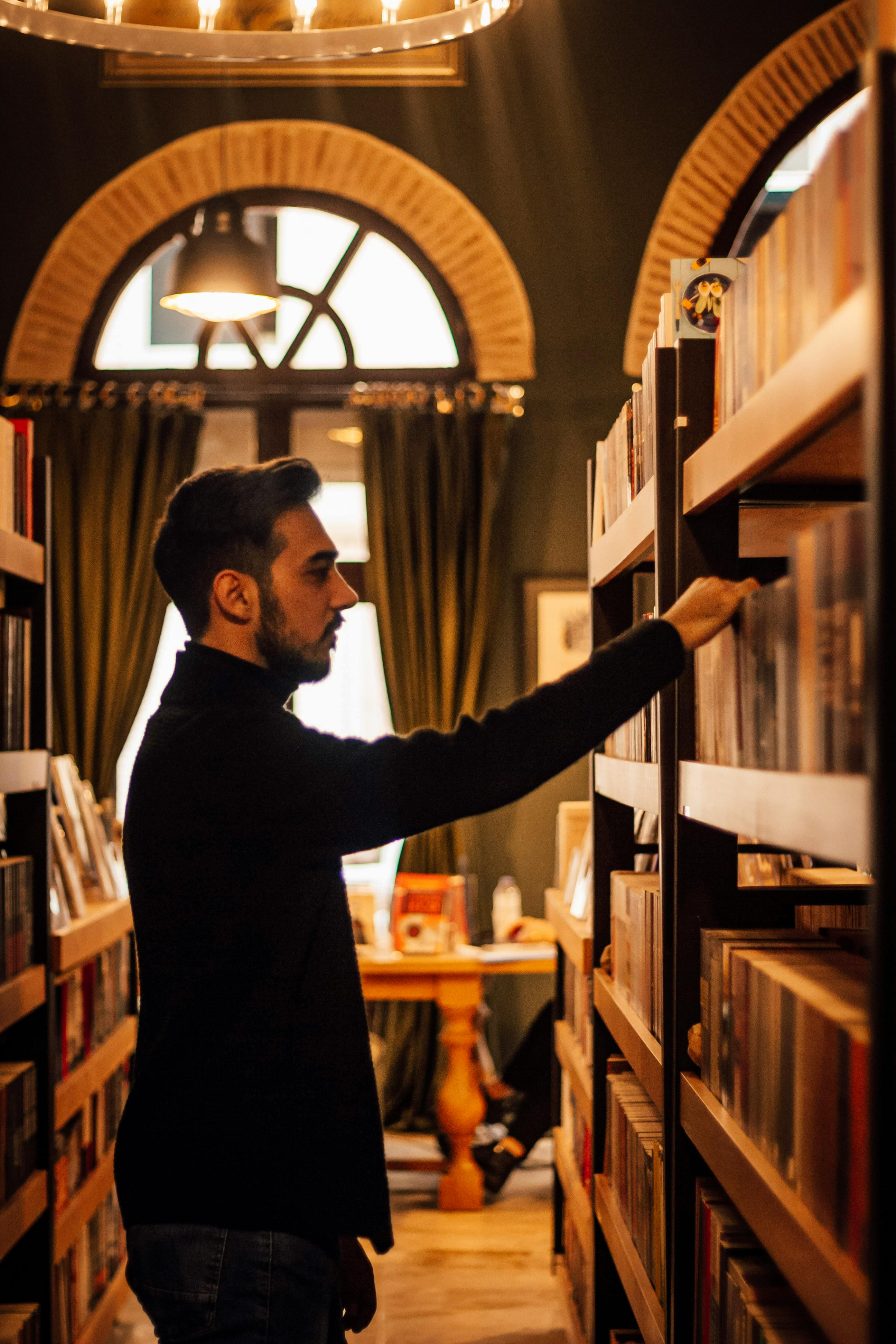 A Man Browsing for Books in a Library · Free Stock Photo