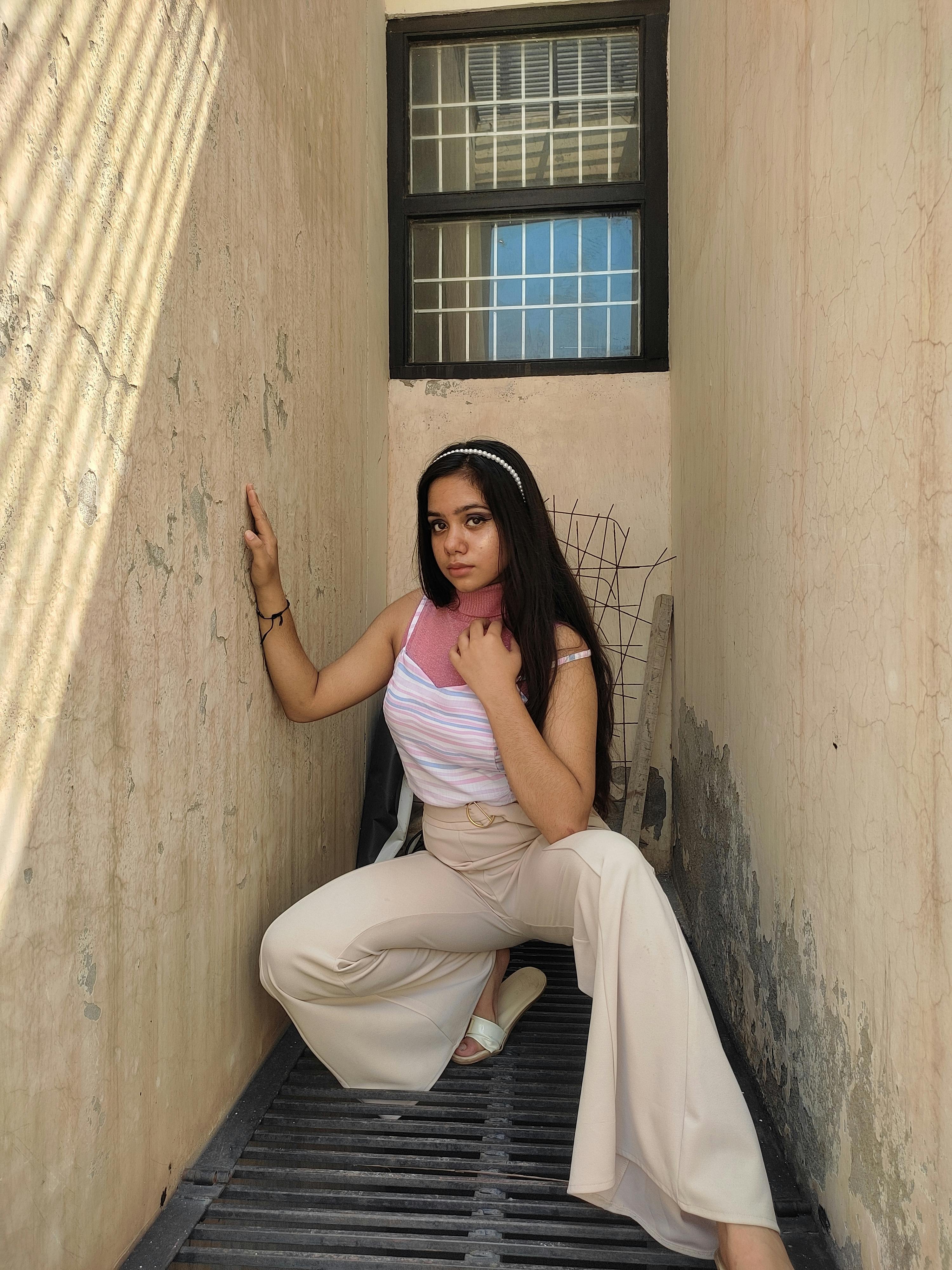 A Girl Crouching between Walls of a Building · Free Stock Photo
