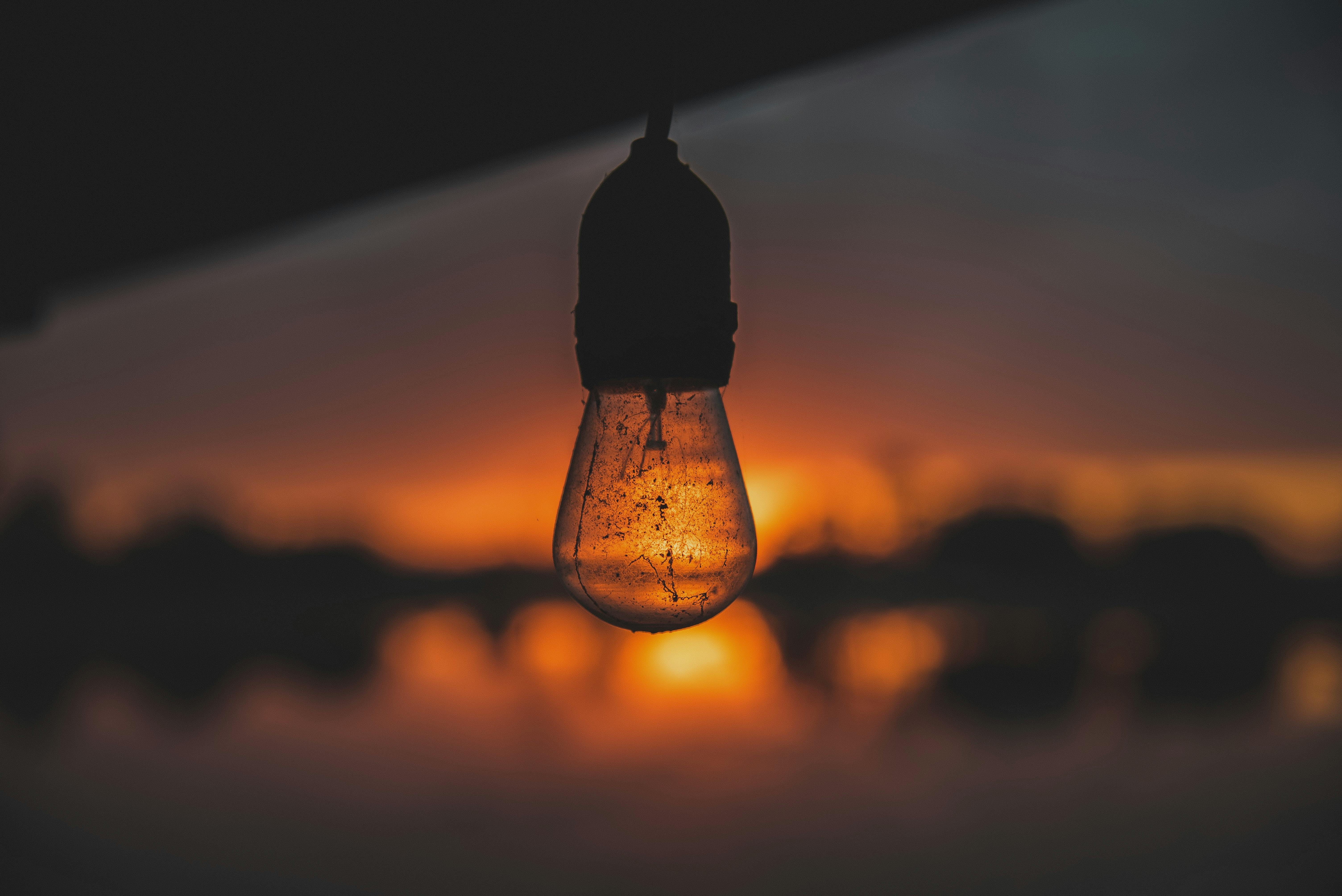 Dirty Light Bulb Hanging Against the Setting Sun · Free Stock Photo