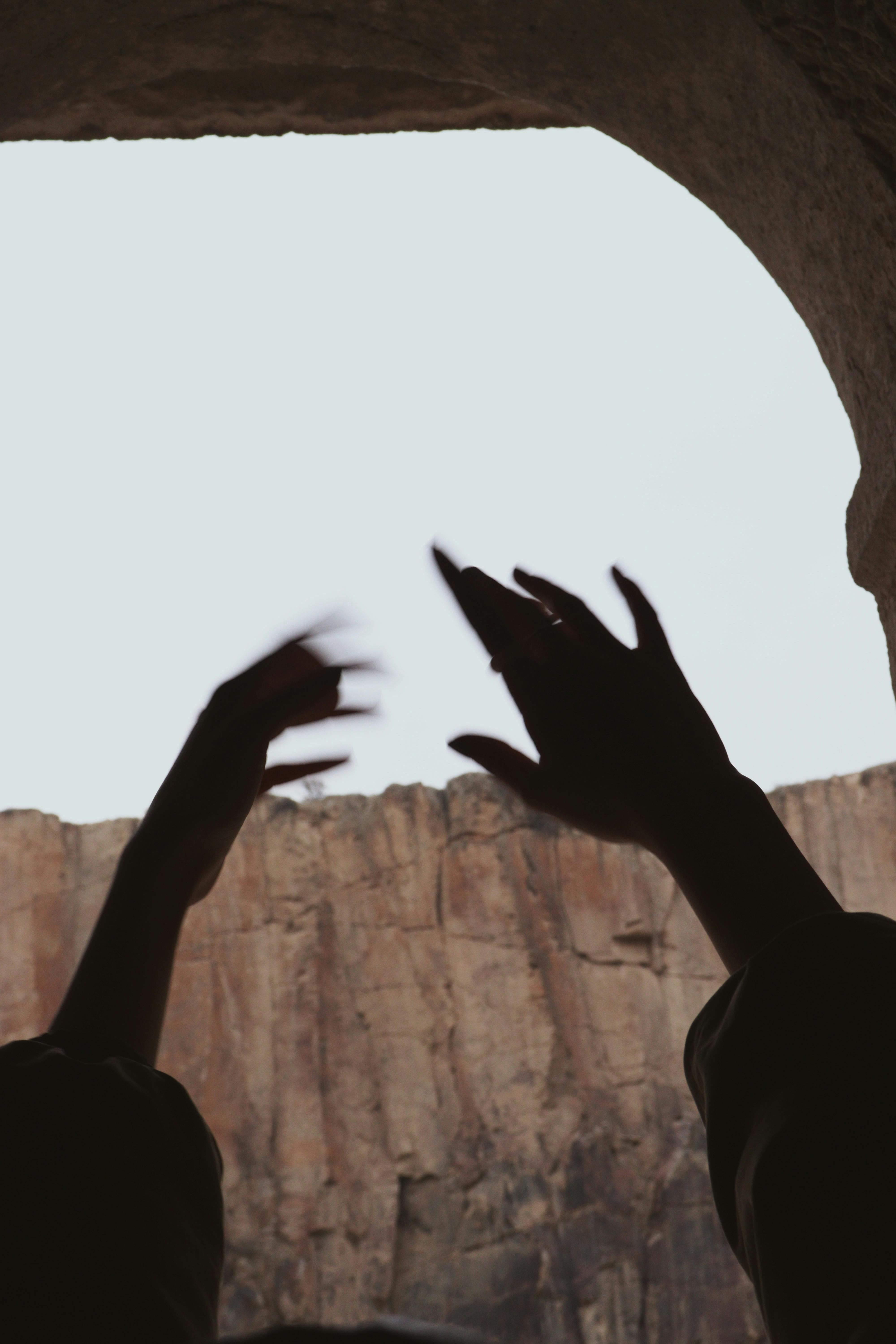 Rocks behind Raised Woman Hands · Free Stock Photo