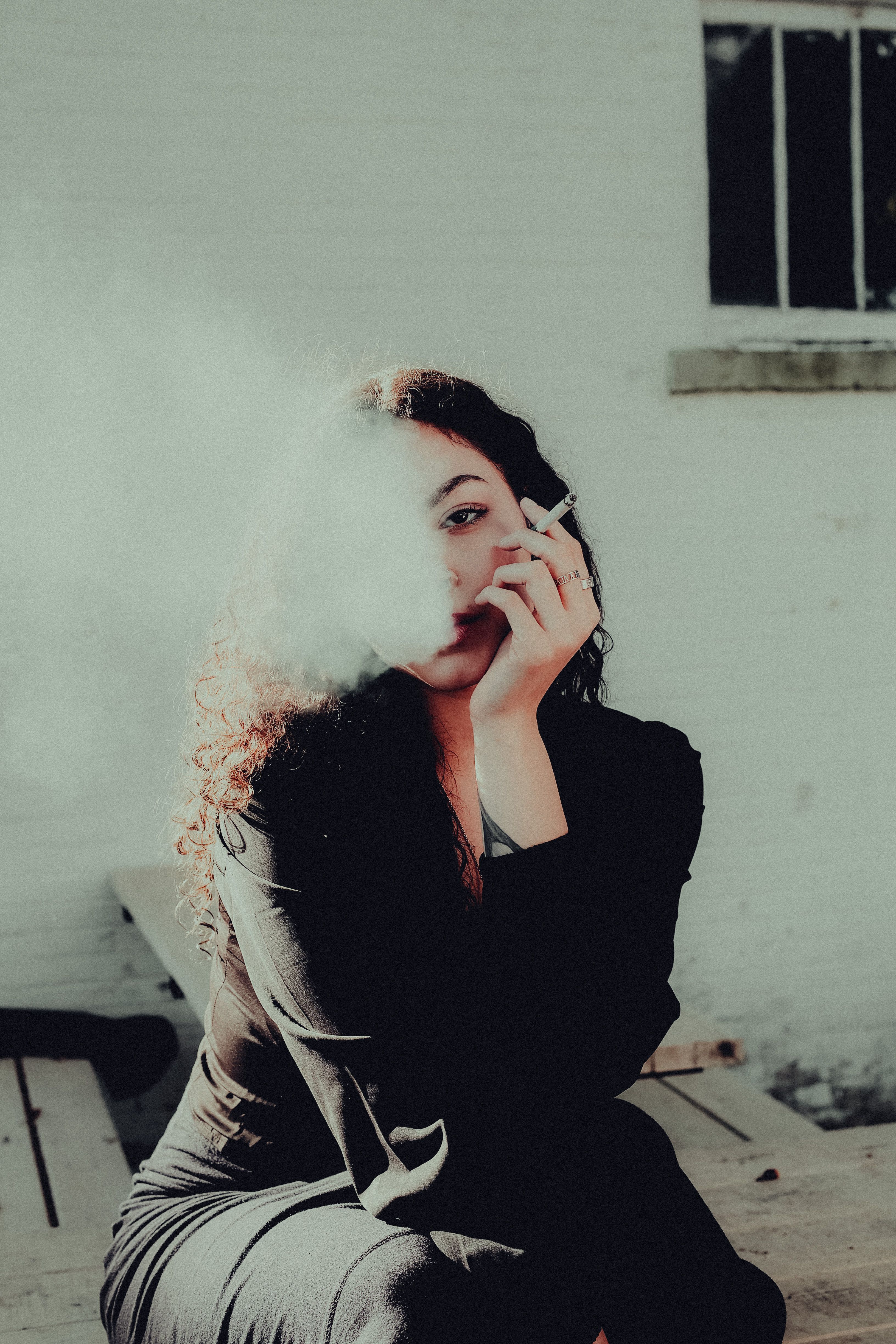 A Woman in Black Outfit Sitting while Smoking Cigarette · Free Stock Photo