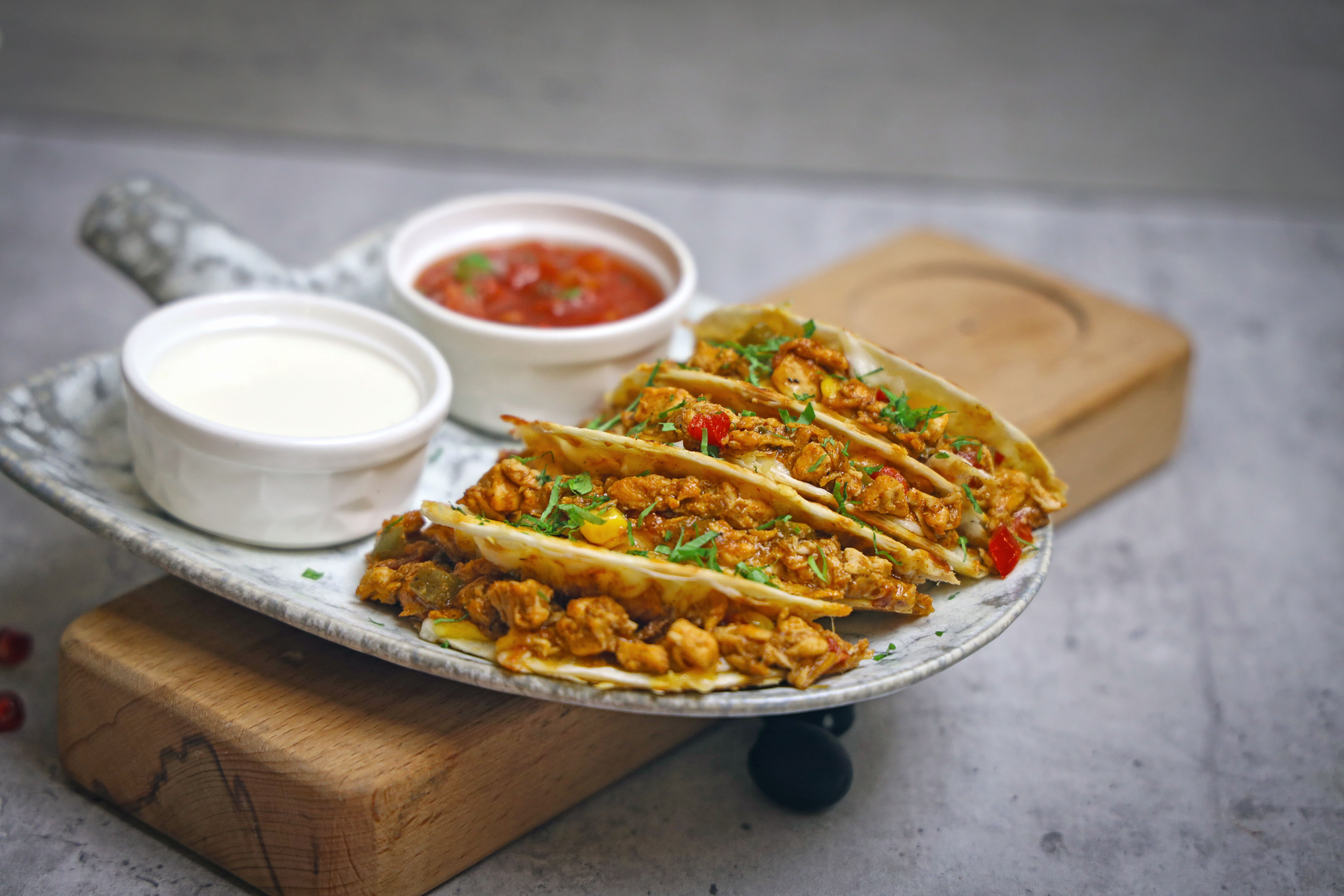 A plate with two tacos and a bowl of sauce · Free Stock Photo