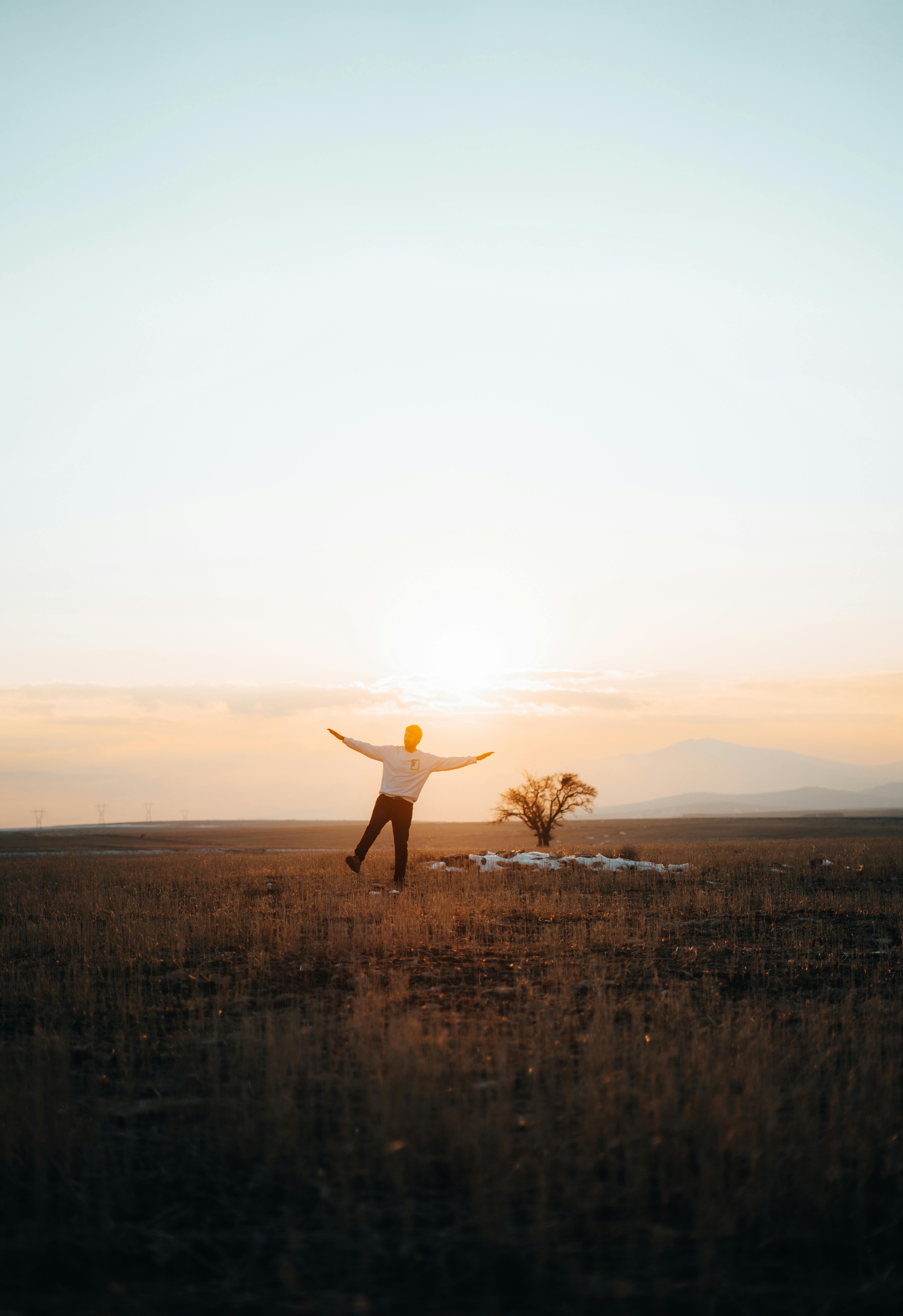 A Man Standing in a Field at Sunset · Free Stock Photo