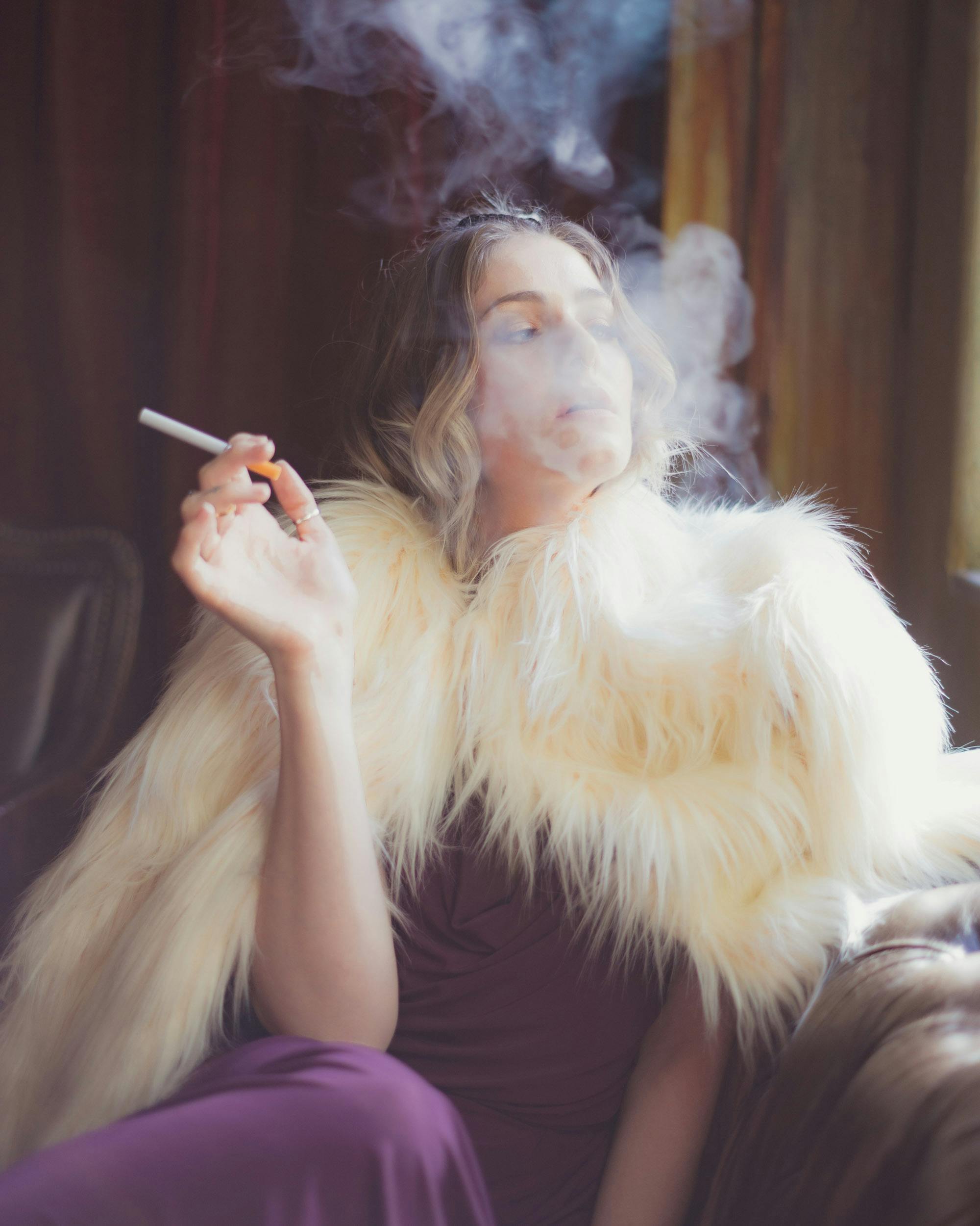 A Woman Sitting on the Couch while Smoking Cigarette · Free Stock Photo