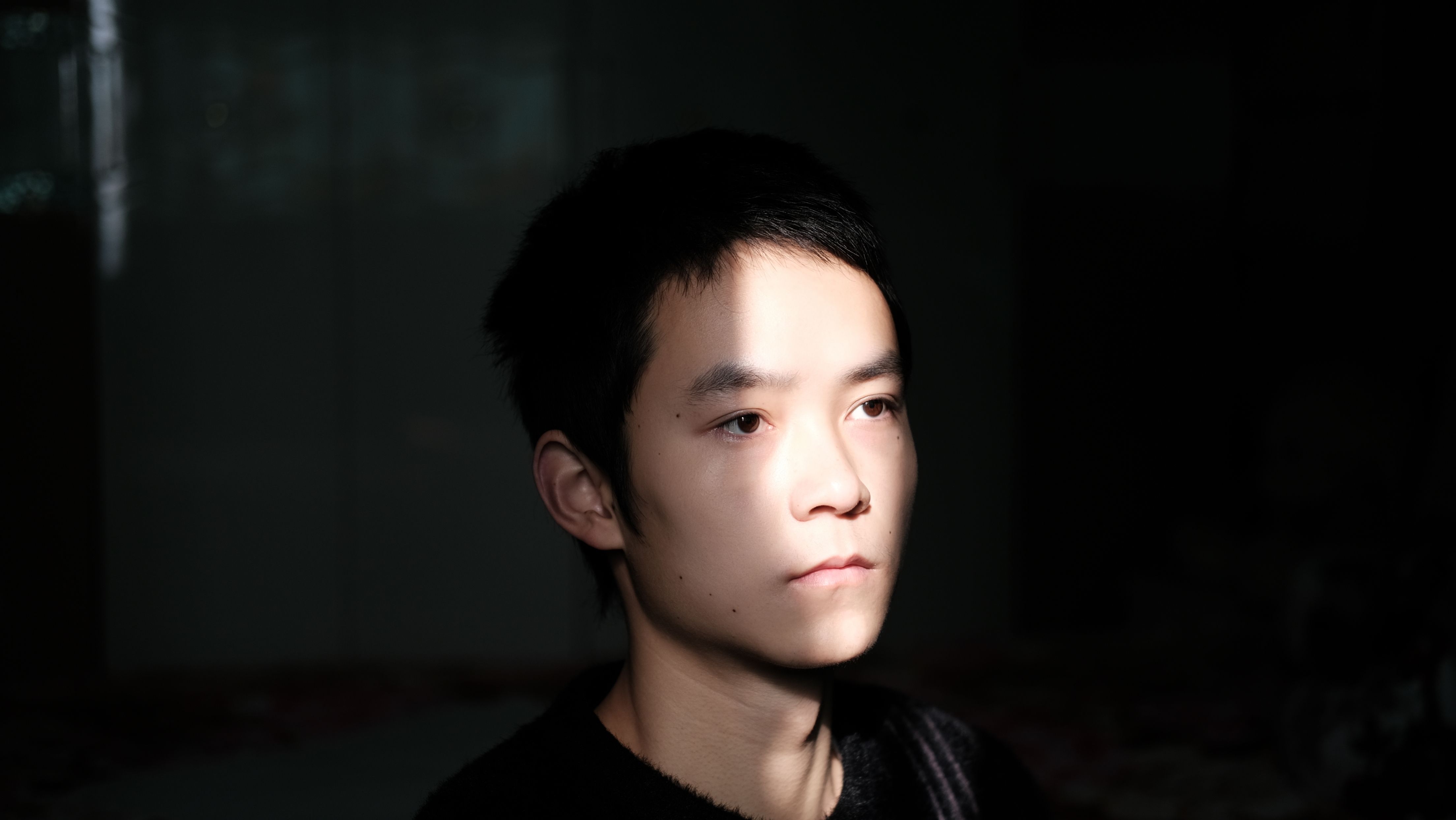Portrait of a Boy Sitting in a Dark Room · Free Stock Photo