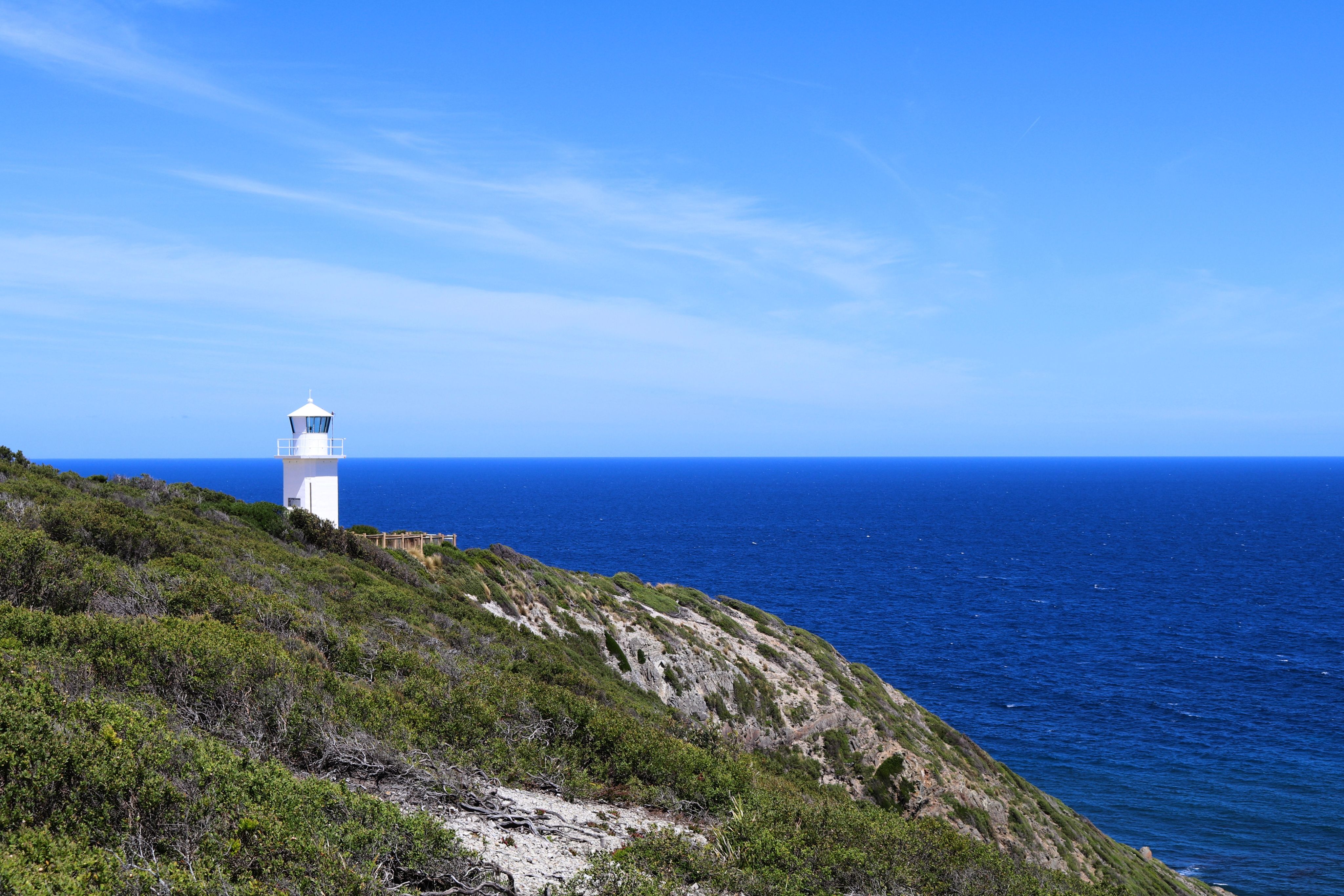 White Lighthouse on Top of Mountain Near Body of Water · Free Stock Photo