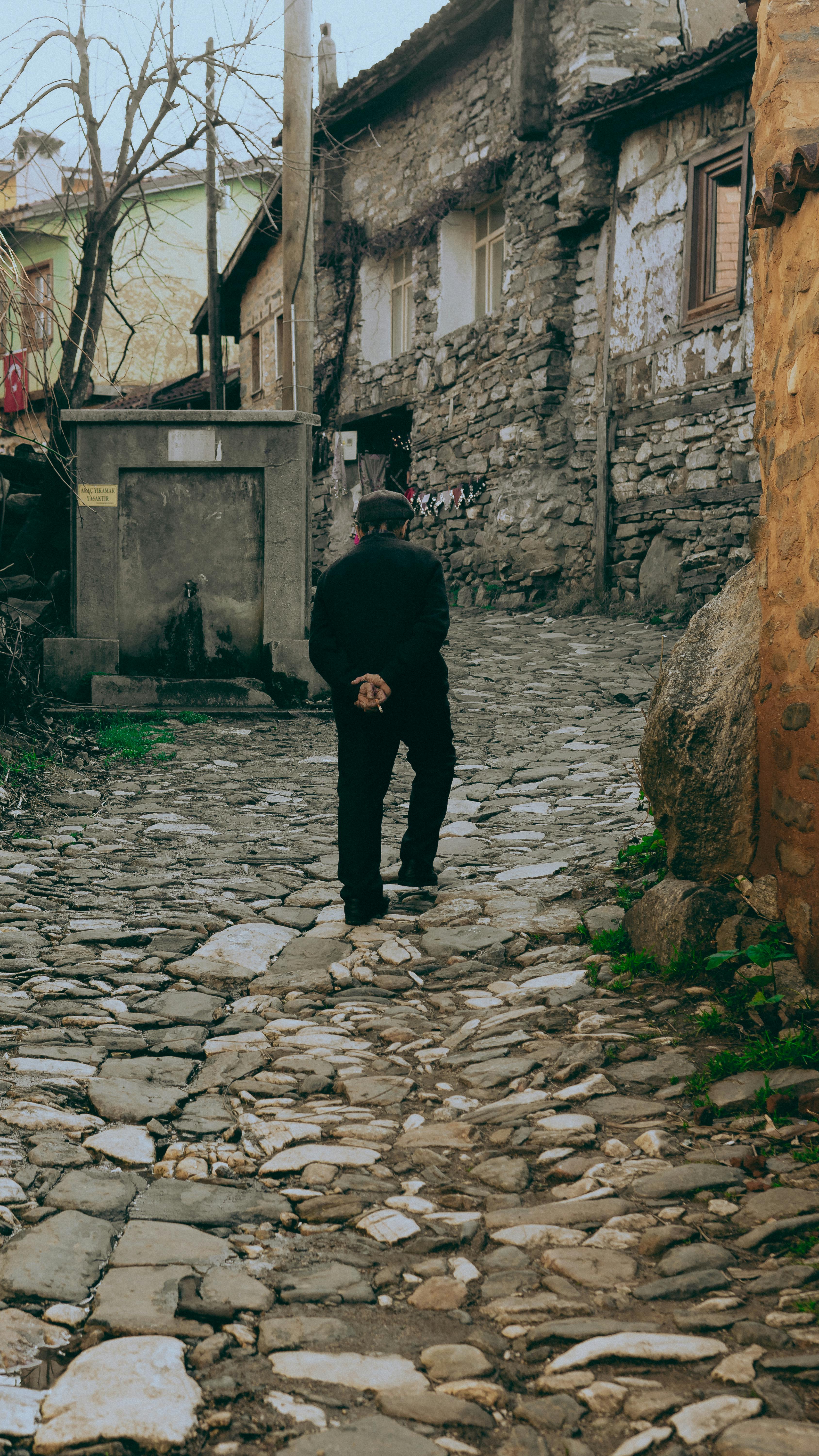 Man Walking on Stone Pavement in an Alley · Free Stock Photo